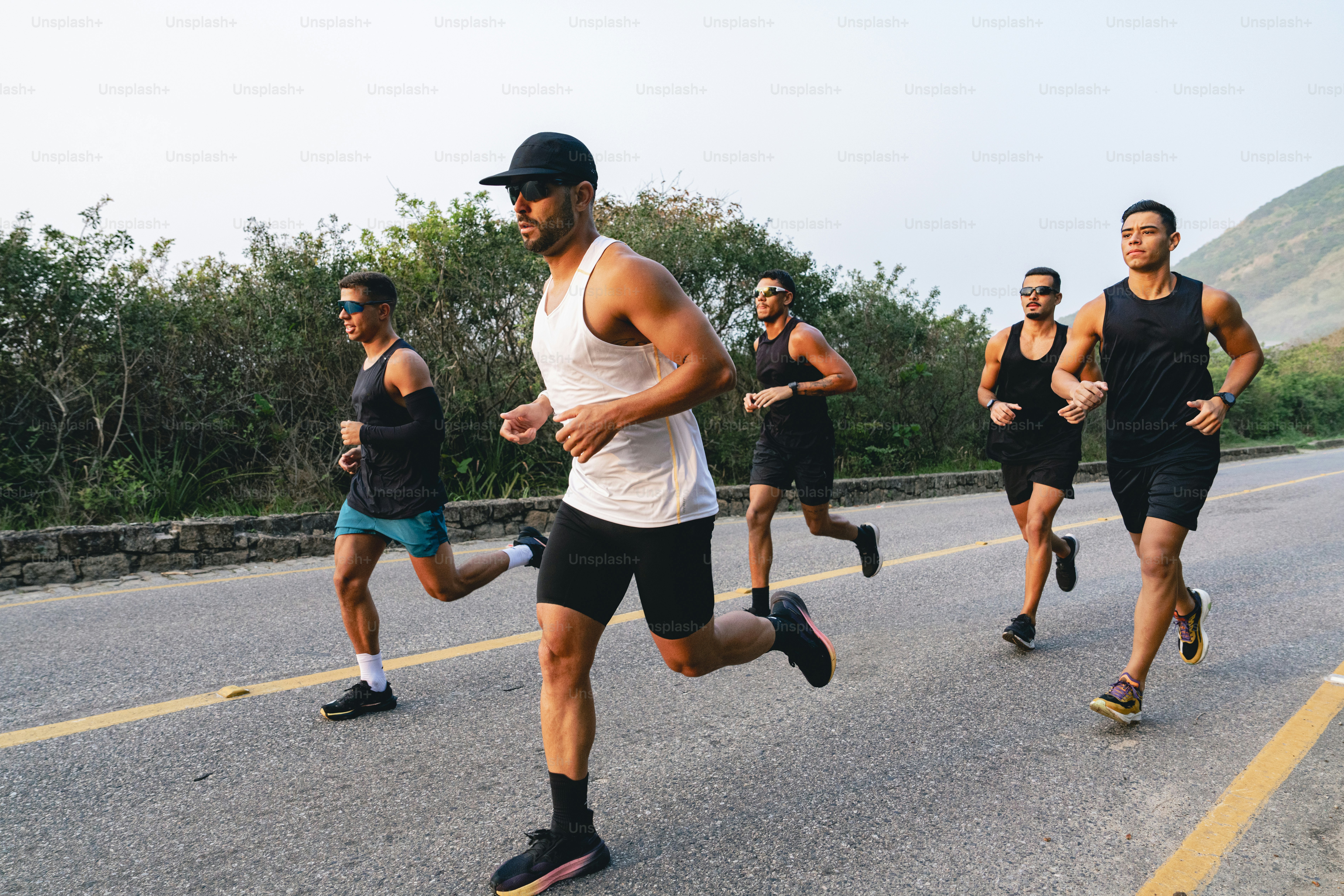 A group of men running down a road photo – Running Image on Unsplash