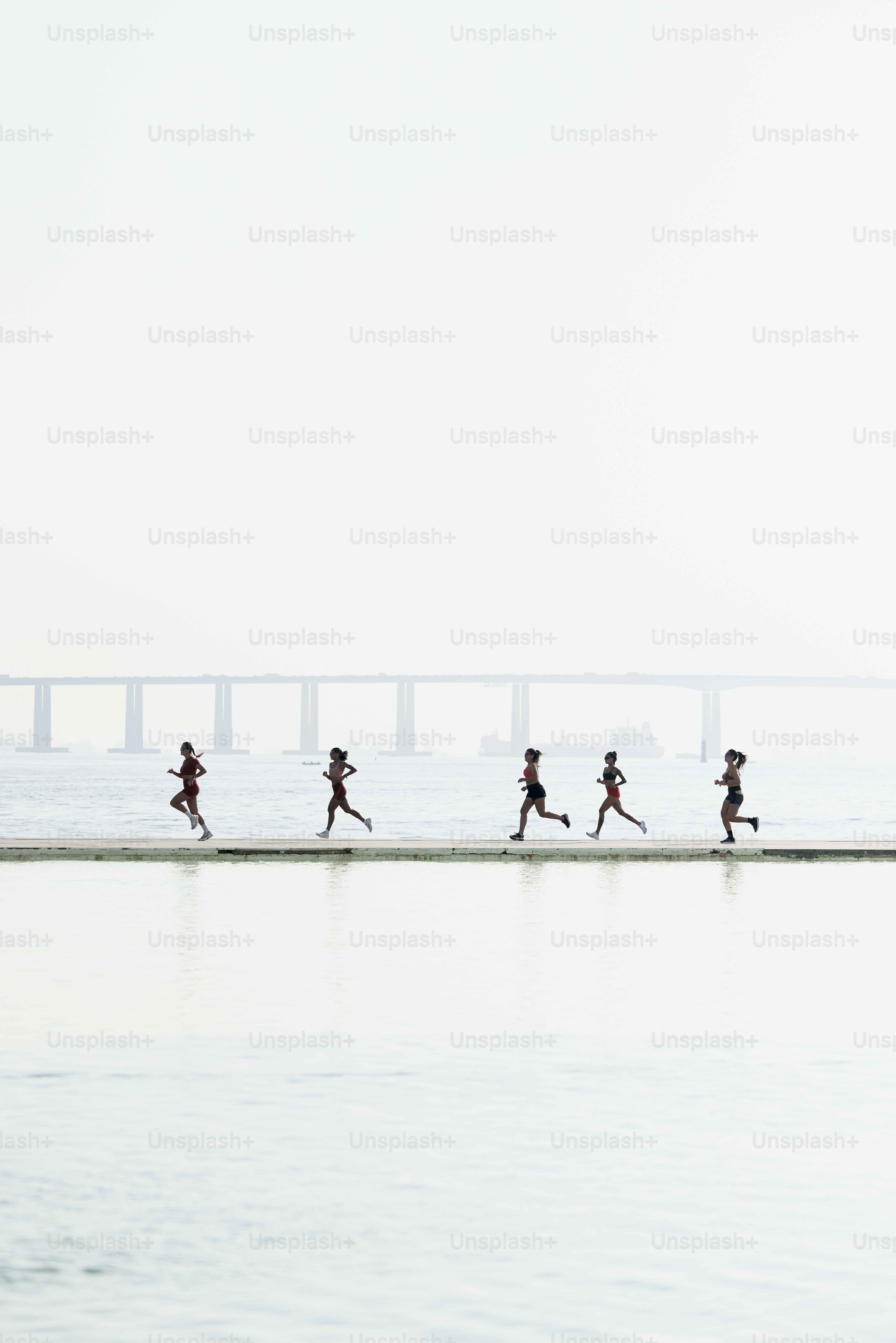A group of people running across a bridge over water photo – Exercise ...