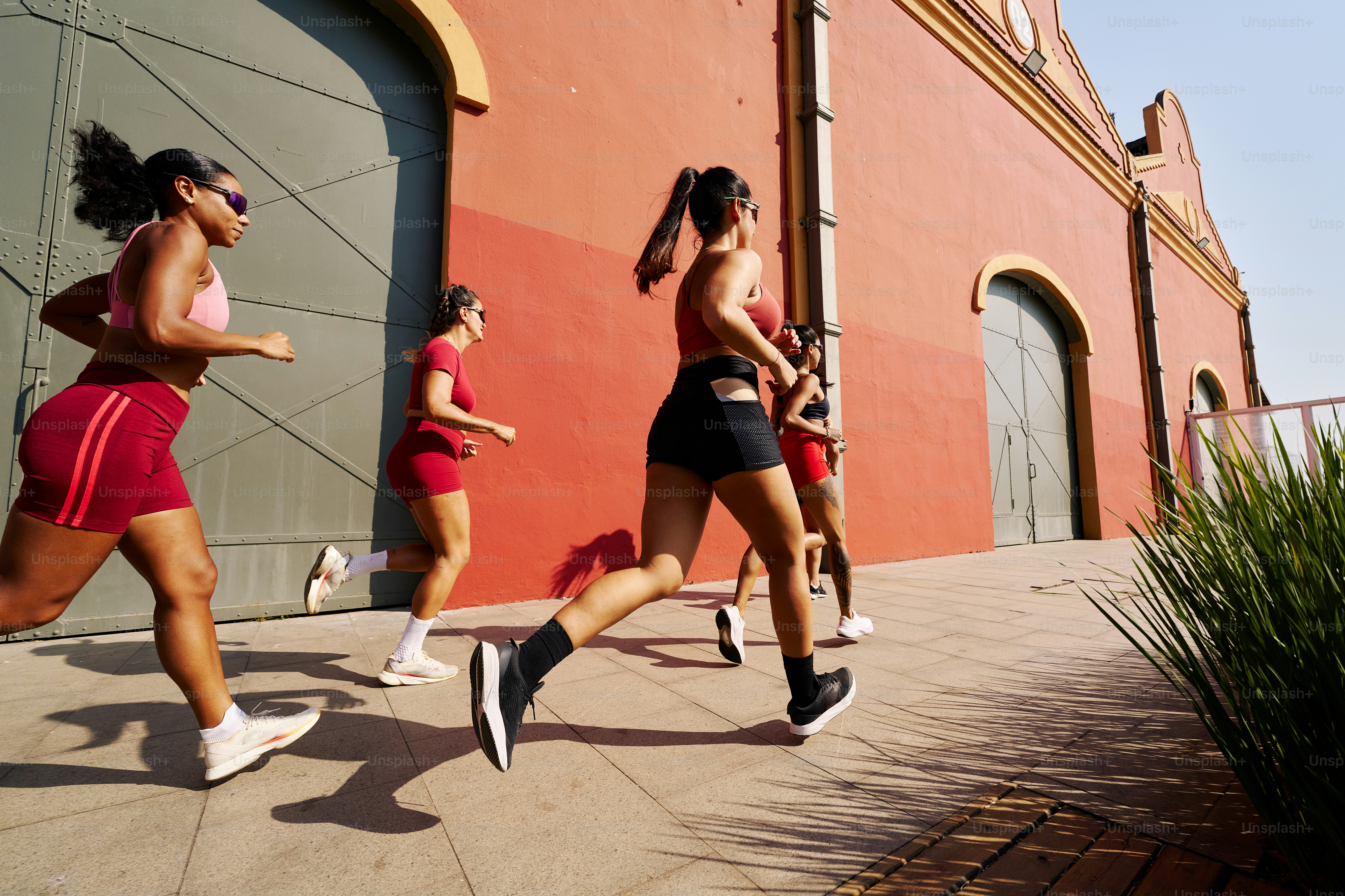 A group of women running down a street next to a building photo ...