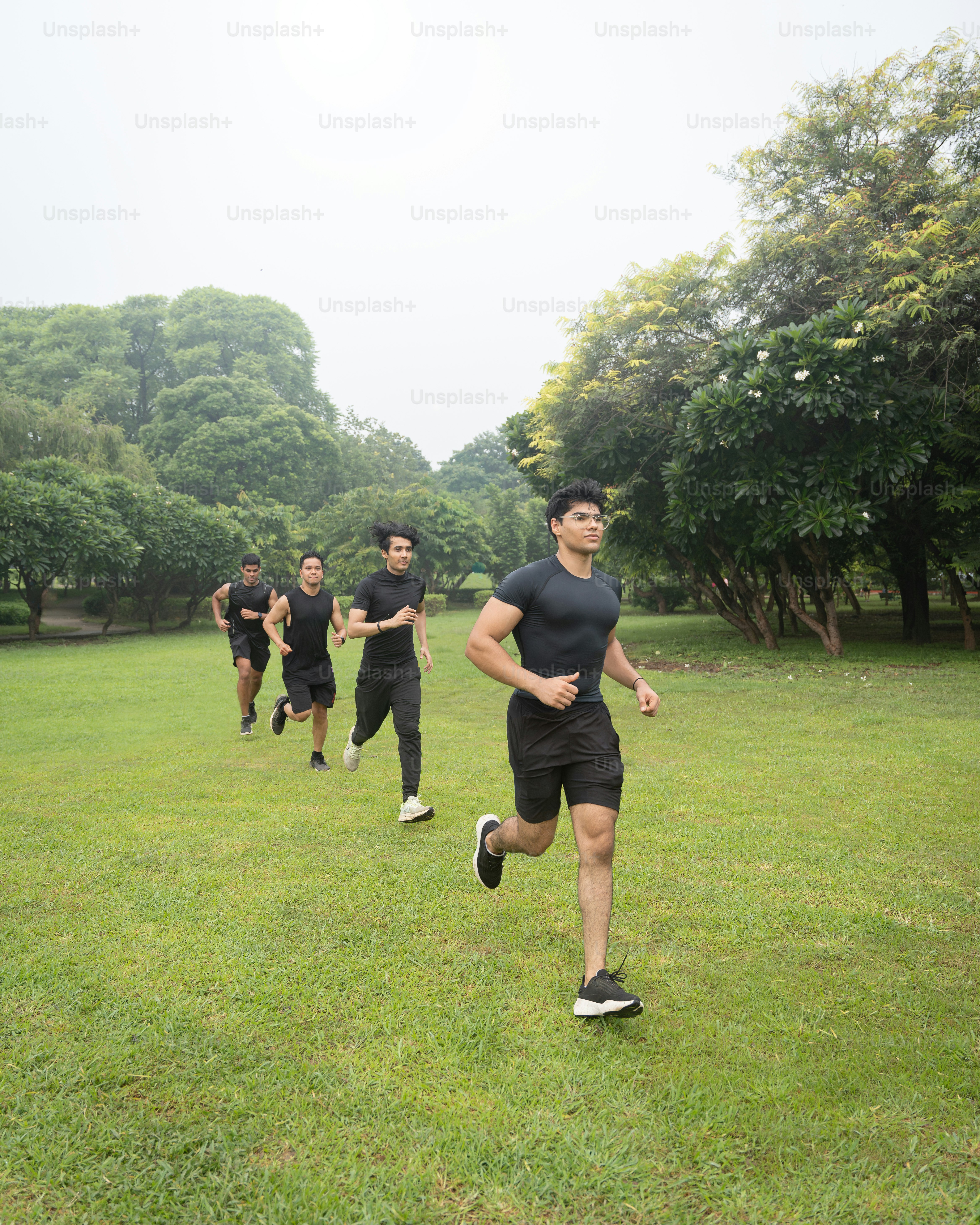 A group of men running across a lush green field photo – Runners Image ...