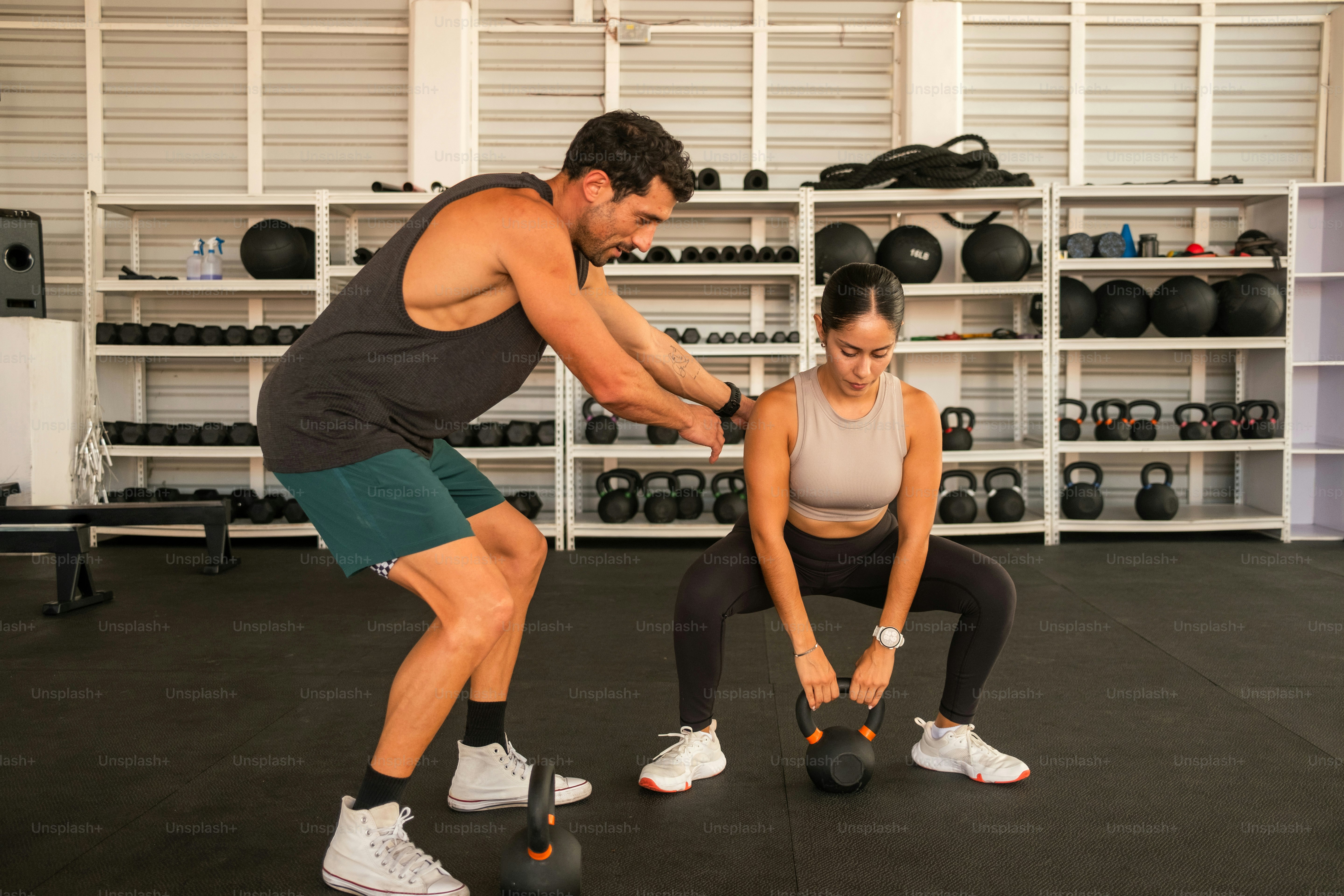 A man and a woman doing squats in a gym photo – Personal trainer Image on Unsplash