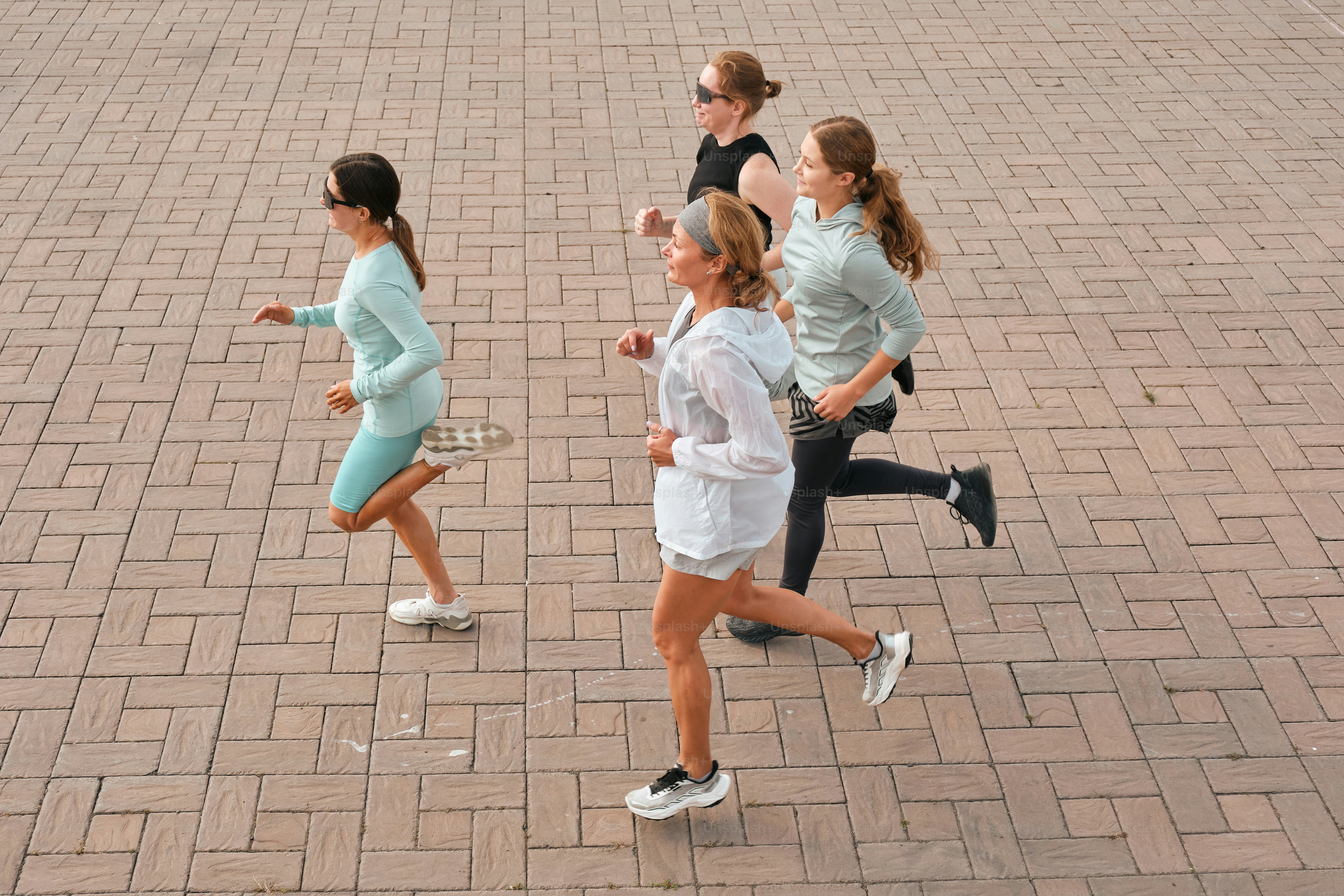 A group of people running on a brick road photo – Fitness Image on Unsplash