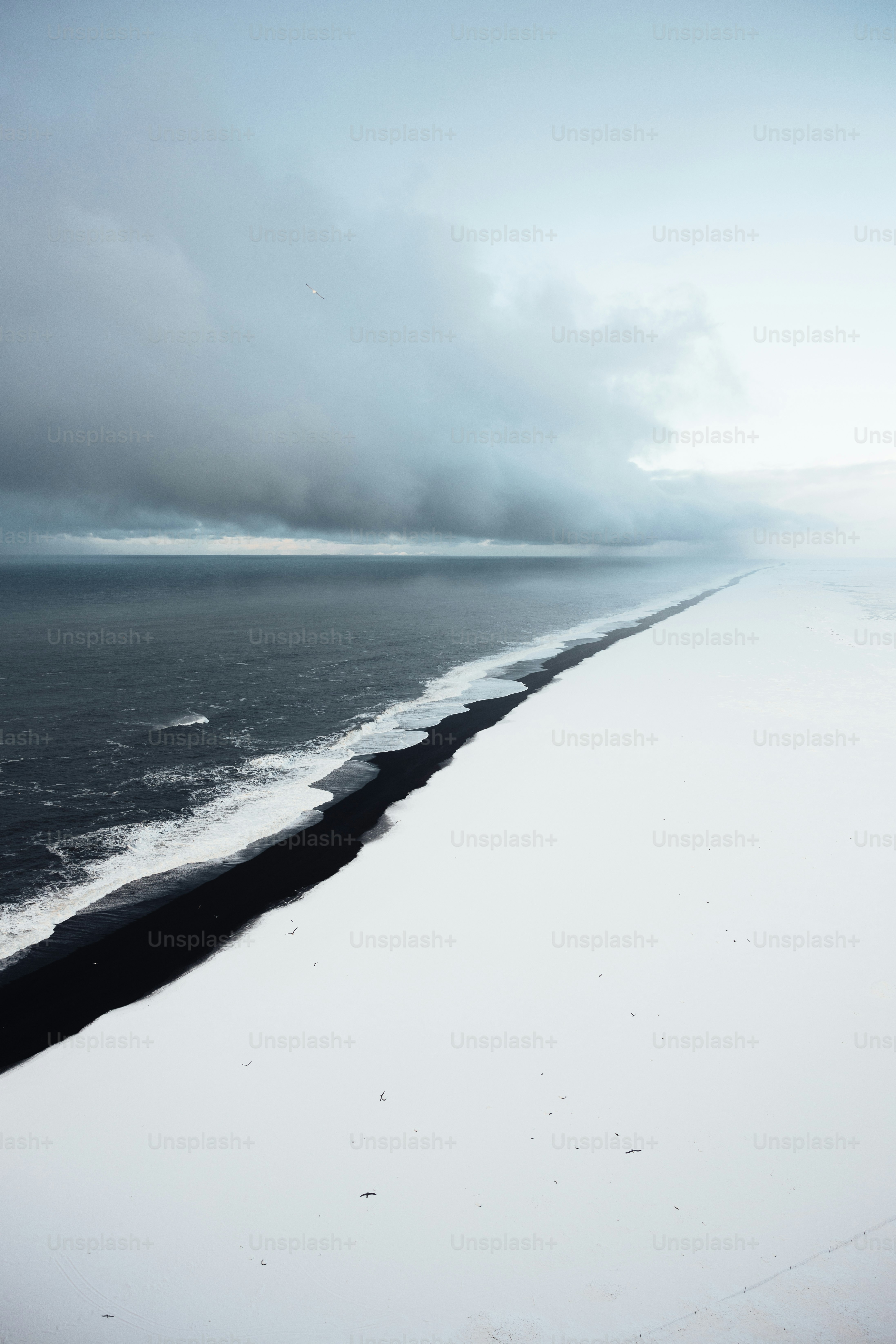 A long stretch of snow covered beach next to the ocean photo – Nature ...