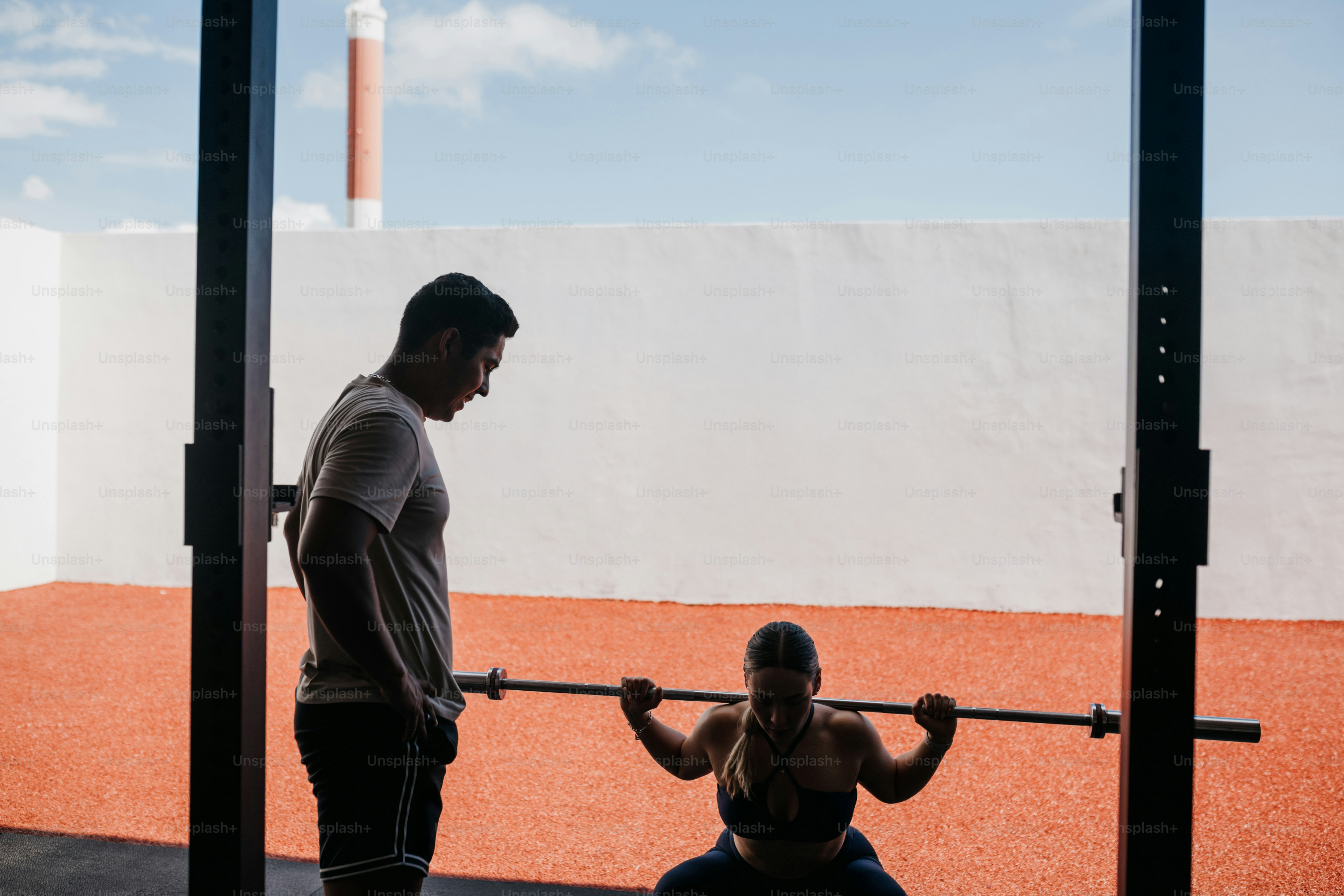 A man and a woman doing squats with barbells photo – Personal training ...