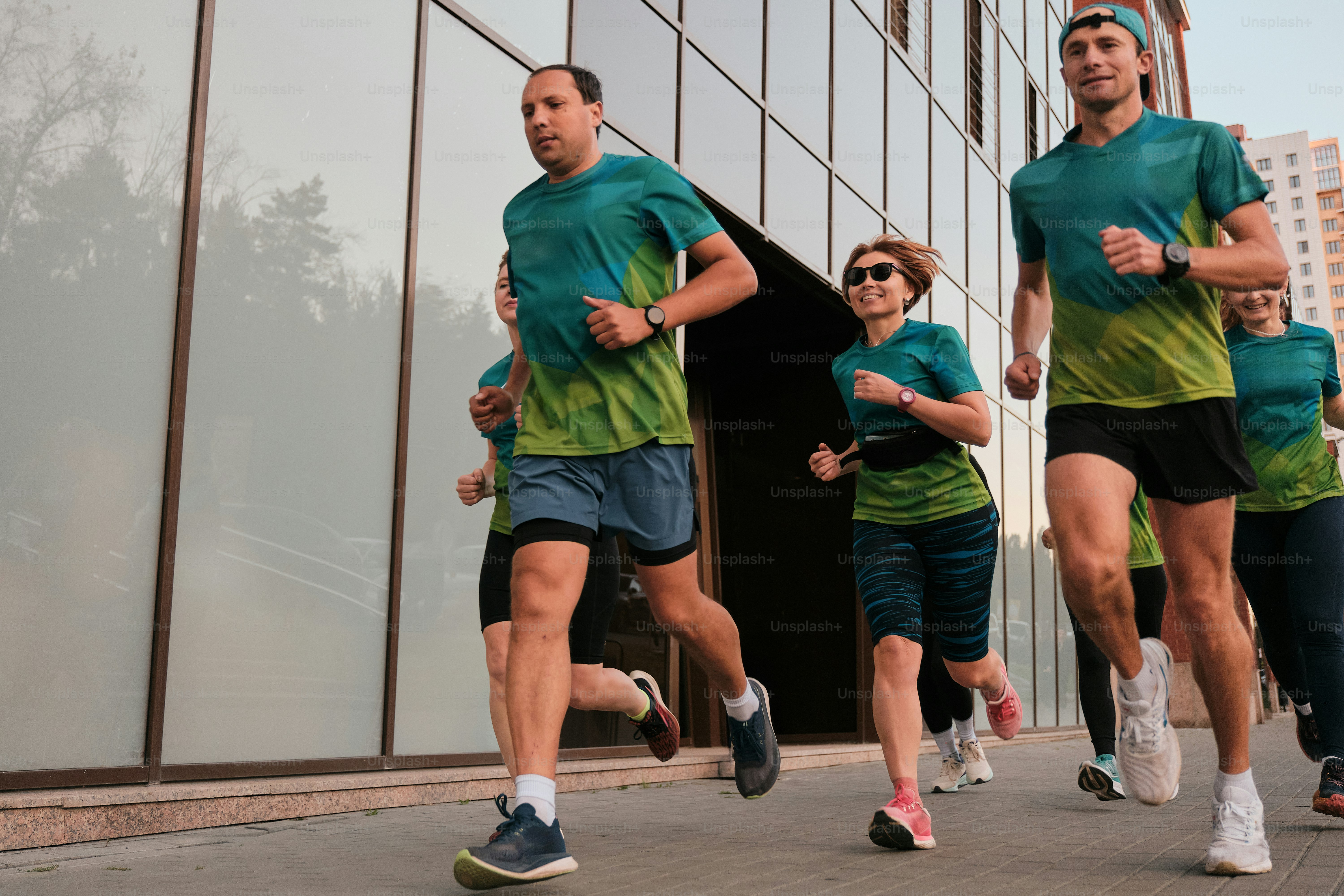 A group of men running down a street next to a tall building photo ...