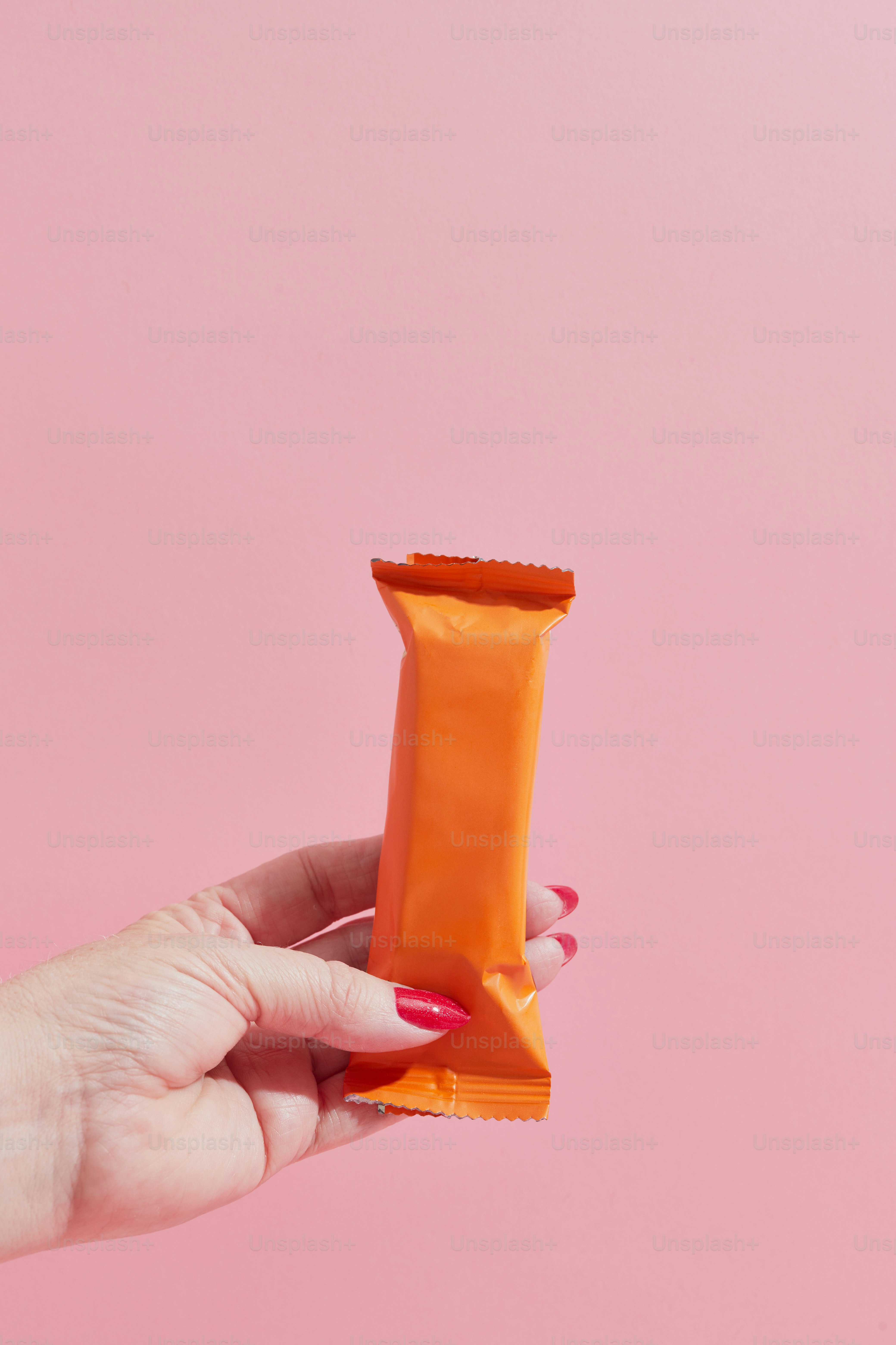 A hand holding a candy bar on a pink background photo – Texture Image ...