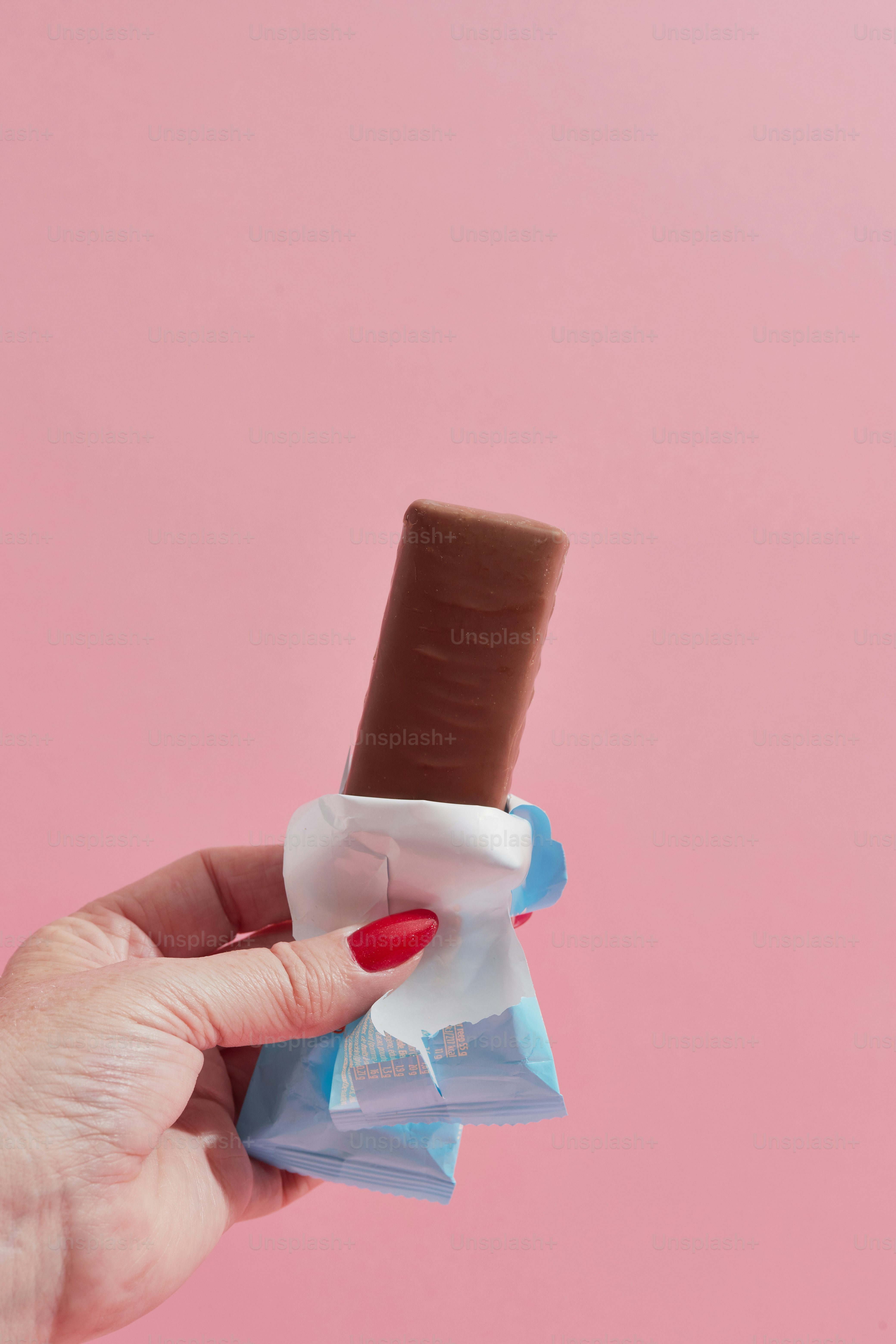 A hand holding a tube of toothpaste on a pink background photo ...