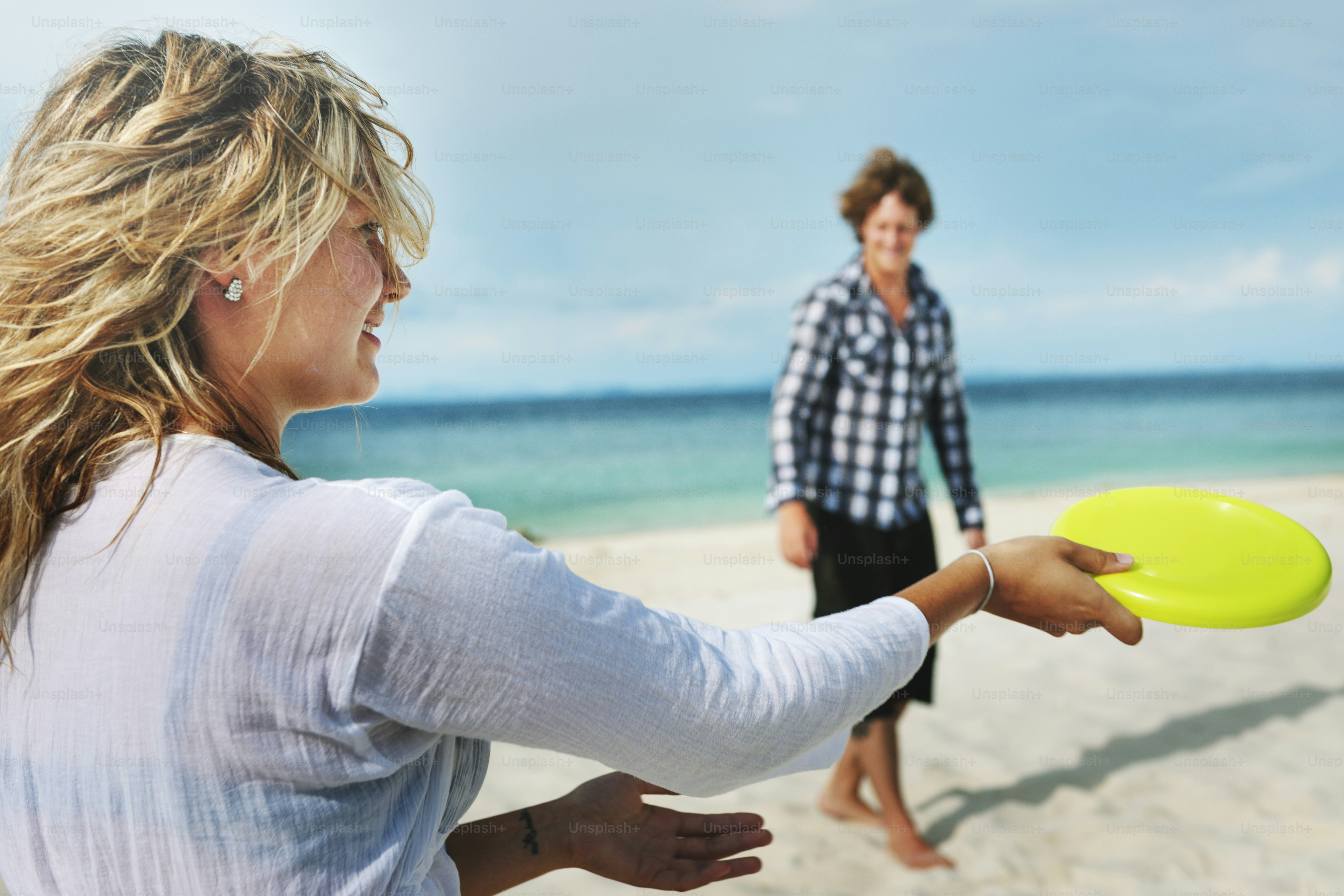 Caucasian friends are playing frisbee together photo – Beach Image on ...