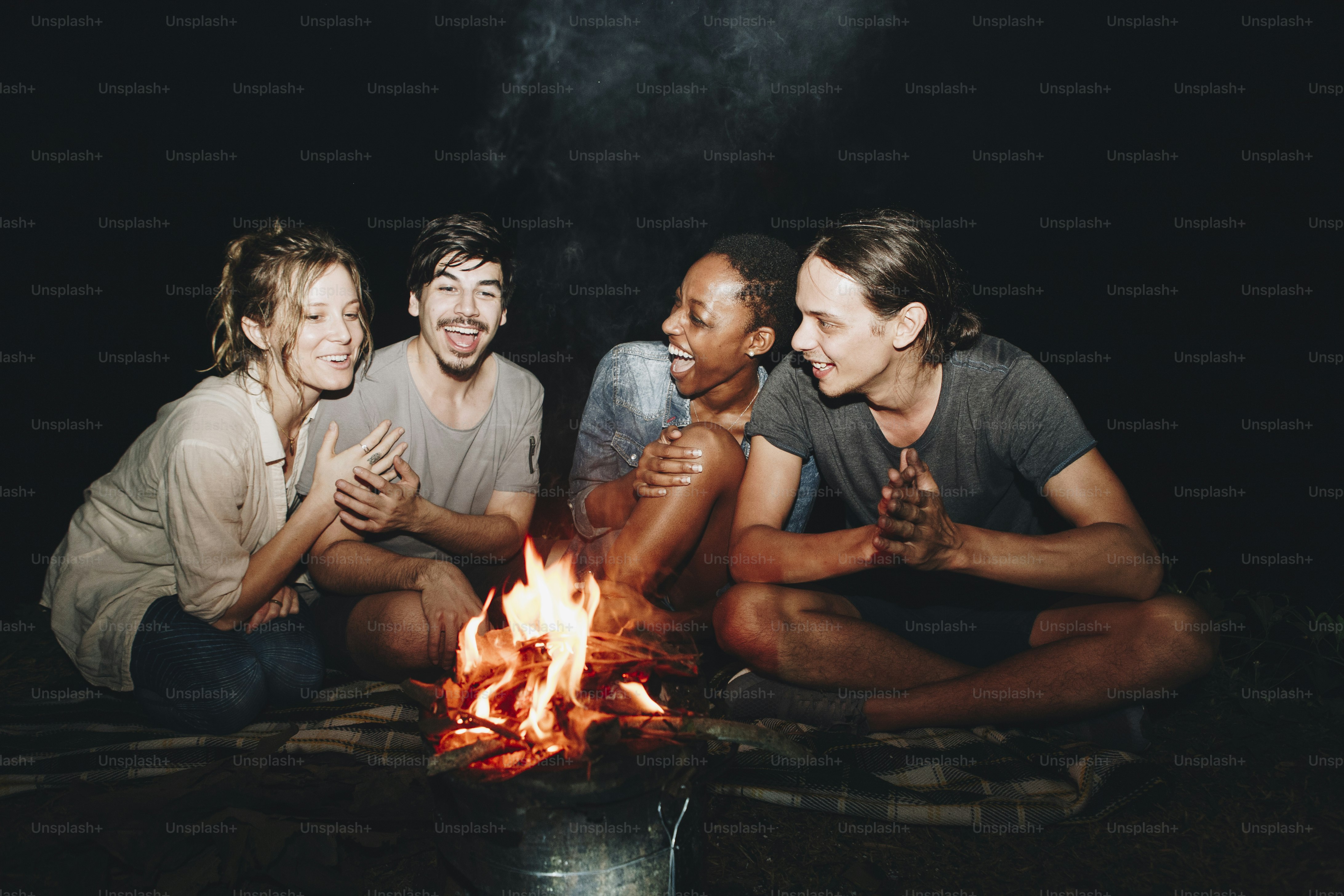 Group of friends sitting around a bonfire at a campsite photo – Dark ...
