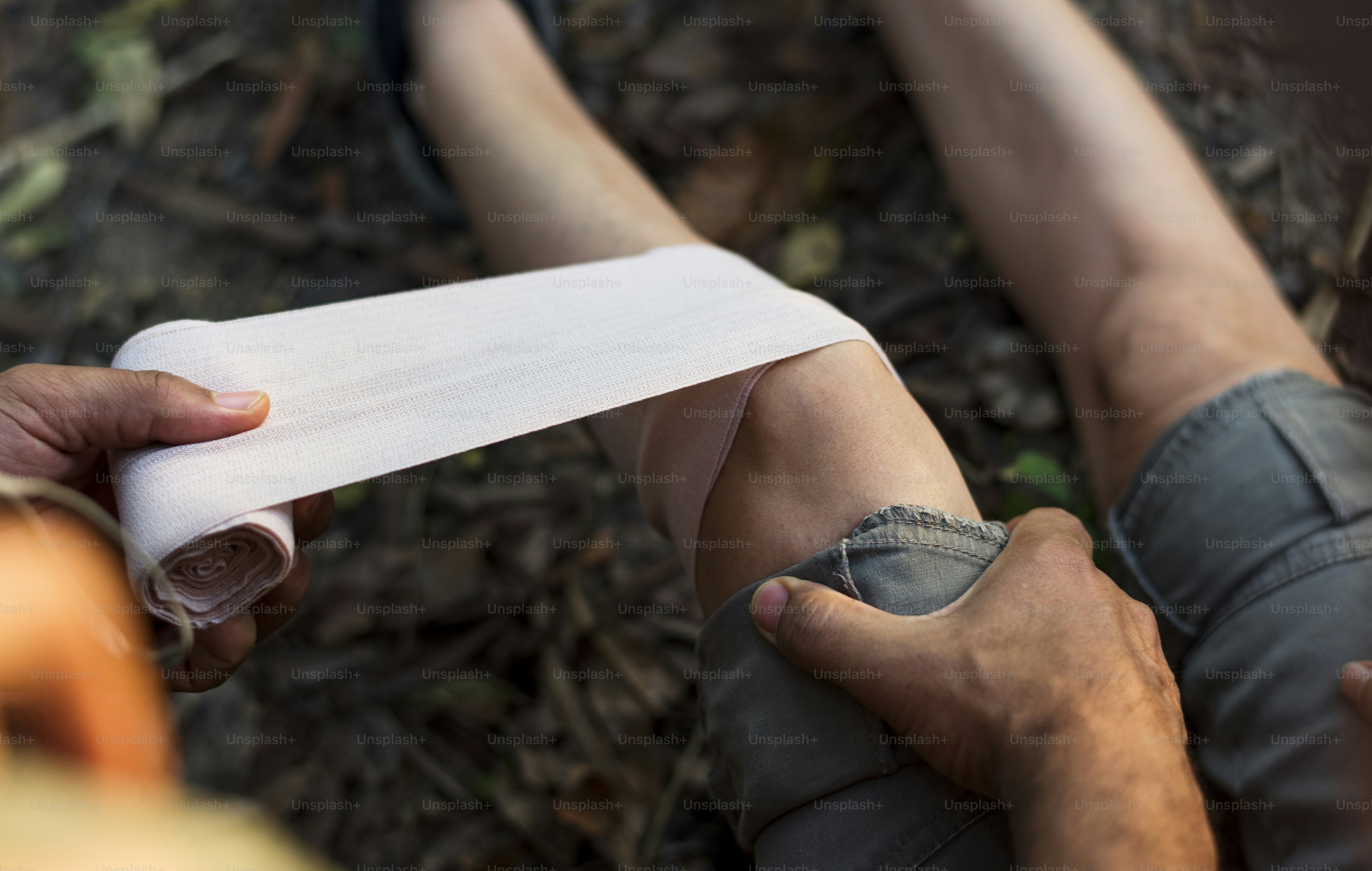 Man putting bandage on his partner's knee in the jungle photo – Couple ...