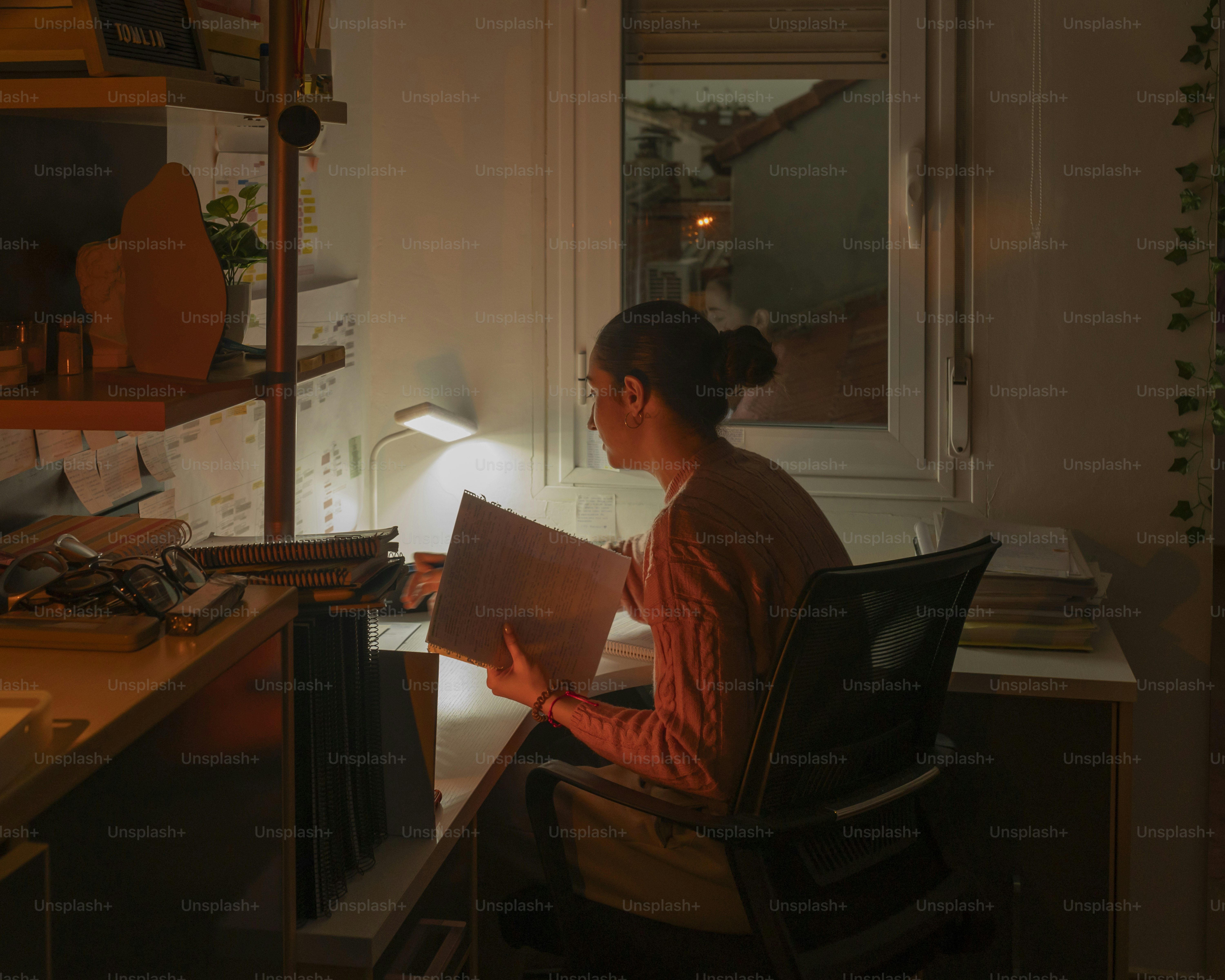 A woman sitting at a desk reading a book photo – Student Image on Unsplash
