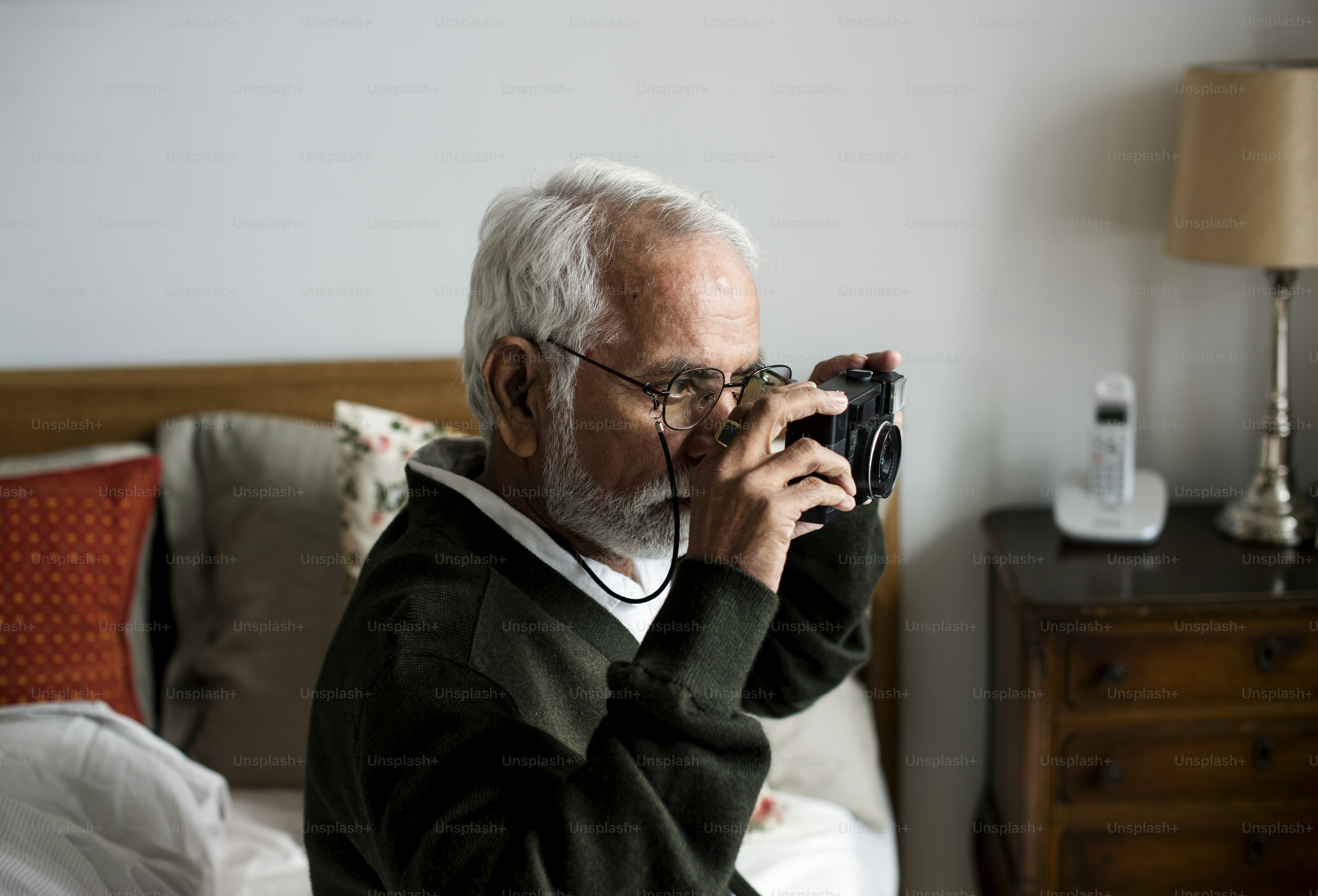 An elderly Indian man at the retirement house taking a photo photo ...