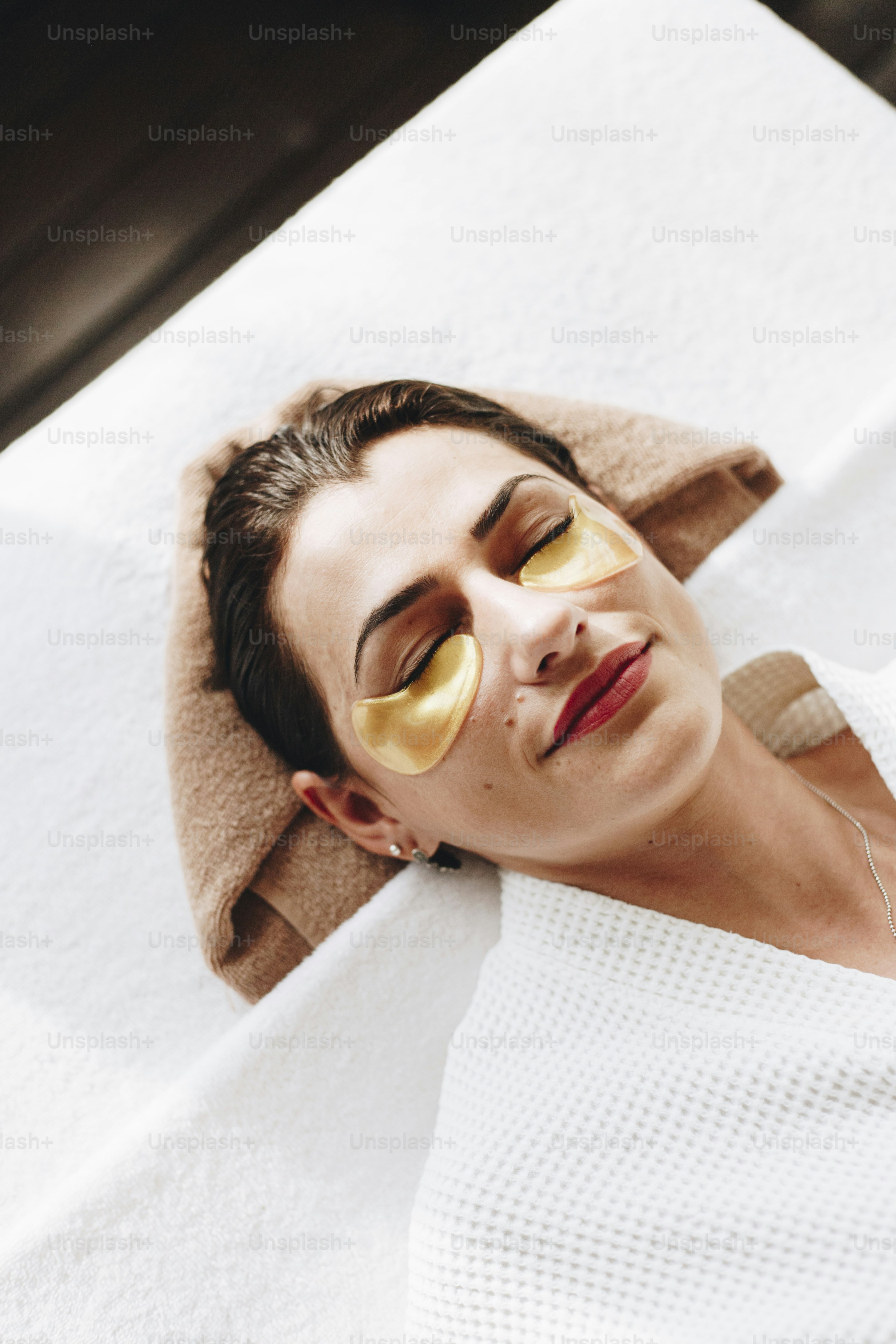 Woman relaxing with a golden eye mask treatment photo – Wellness Image ...