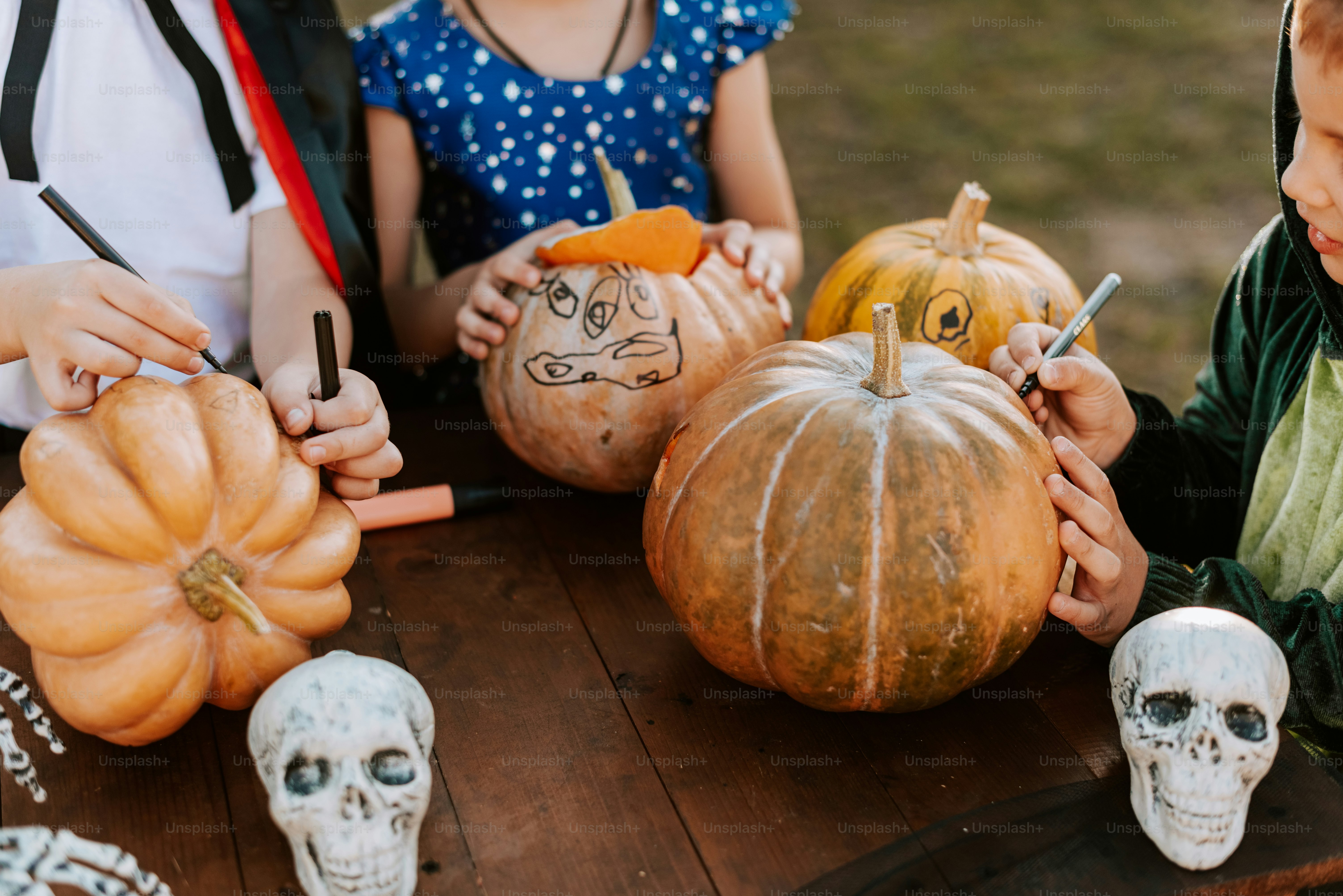 A group of children sitting around a table with pumpkins photo ...