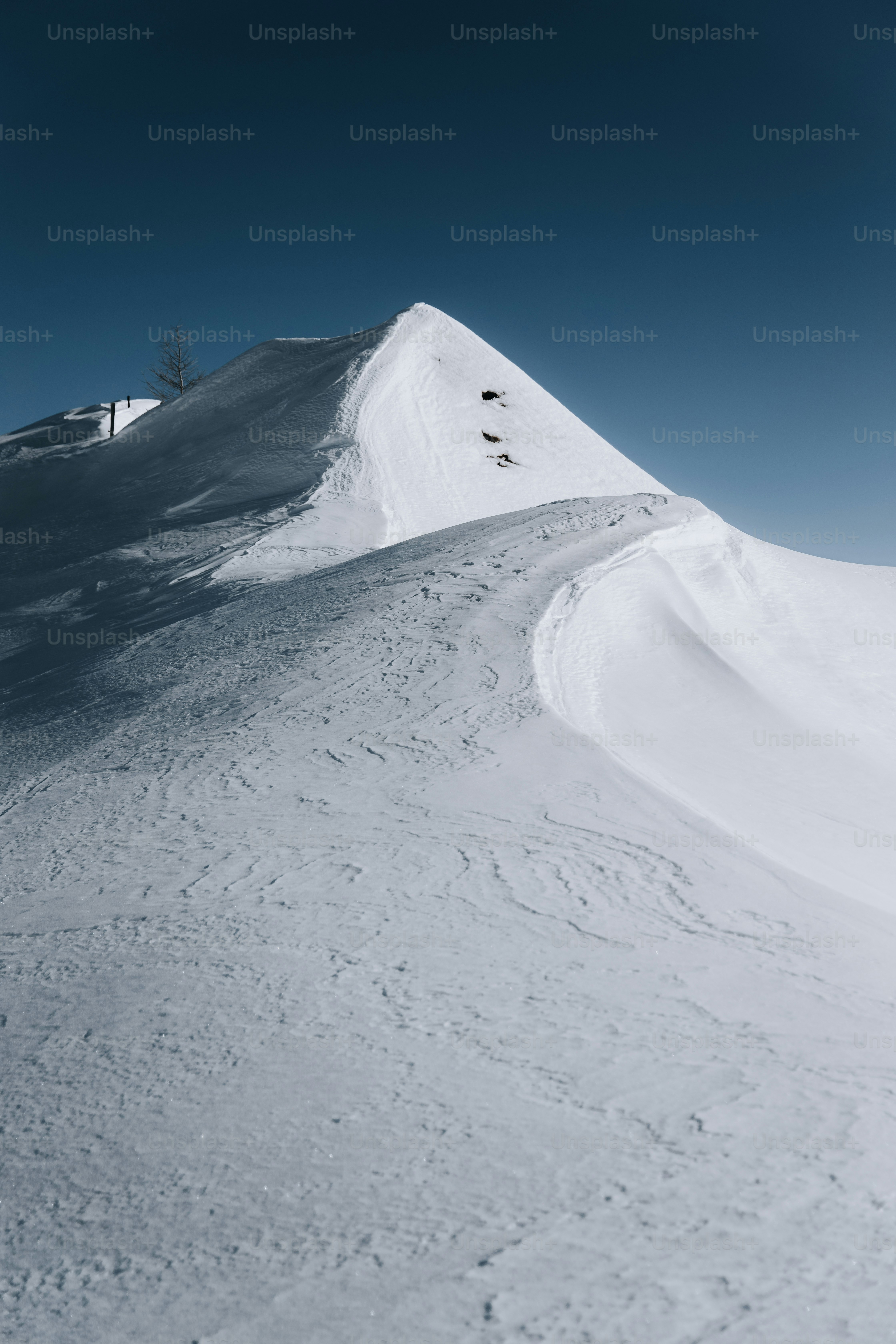 A man riding a snowboard down the side of a snow covered slope photo ...