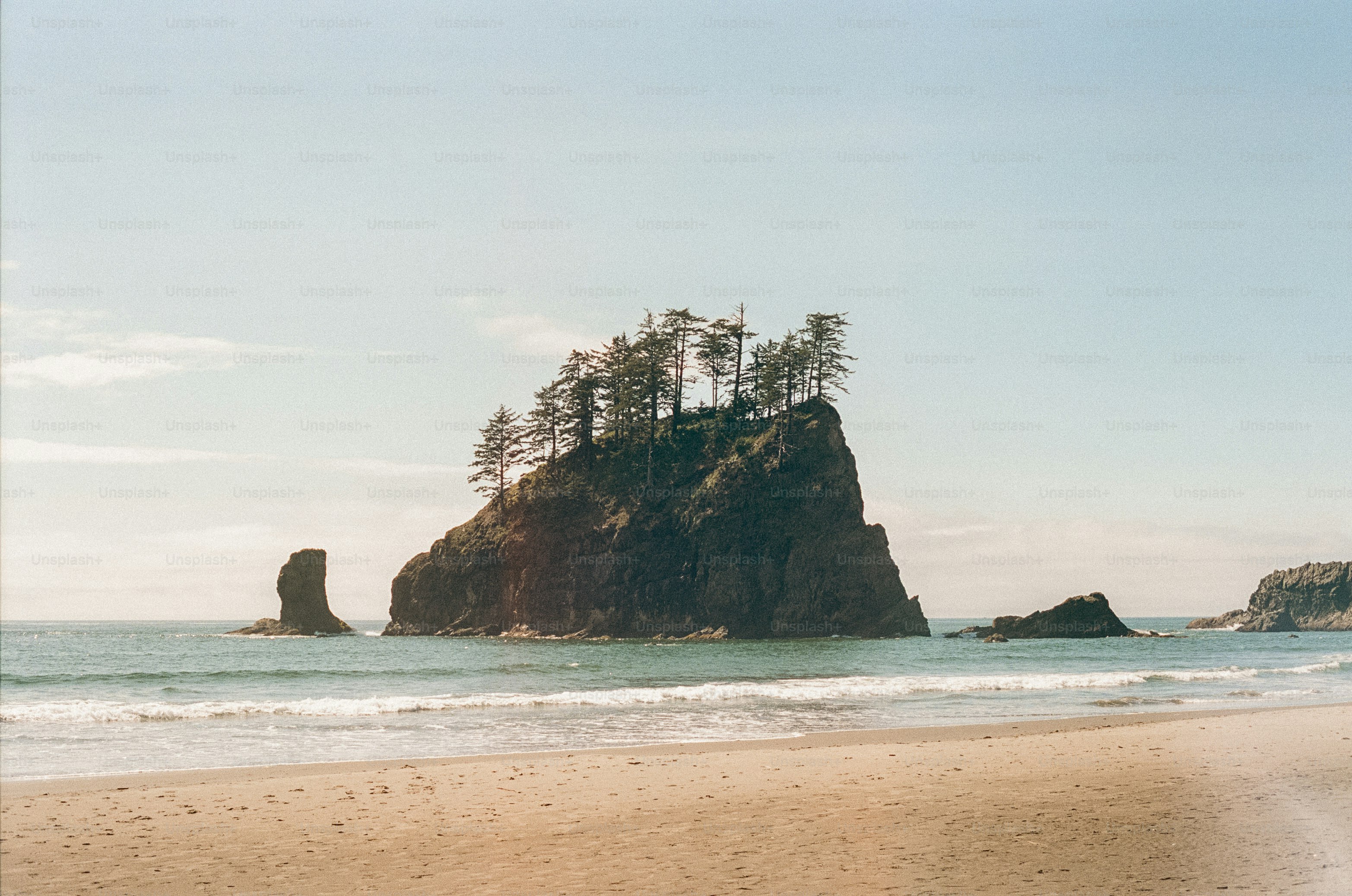 Una playa de arena con una formación rocosa al fondo foto – Imagen de ...