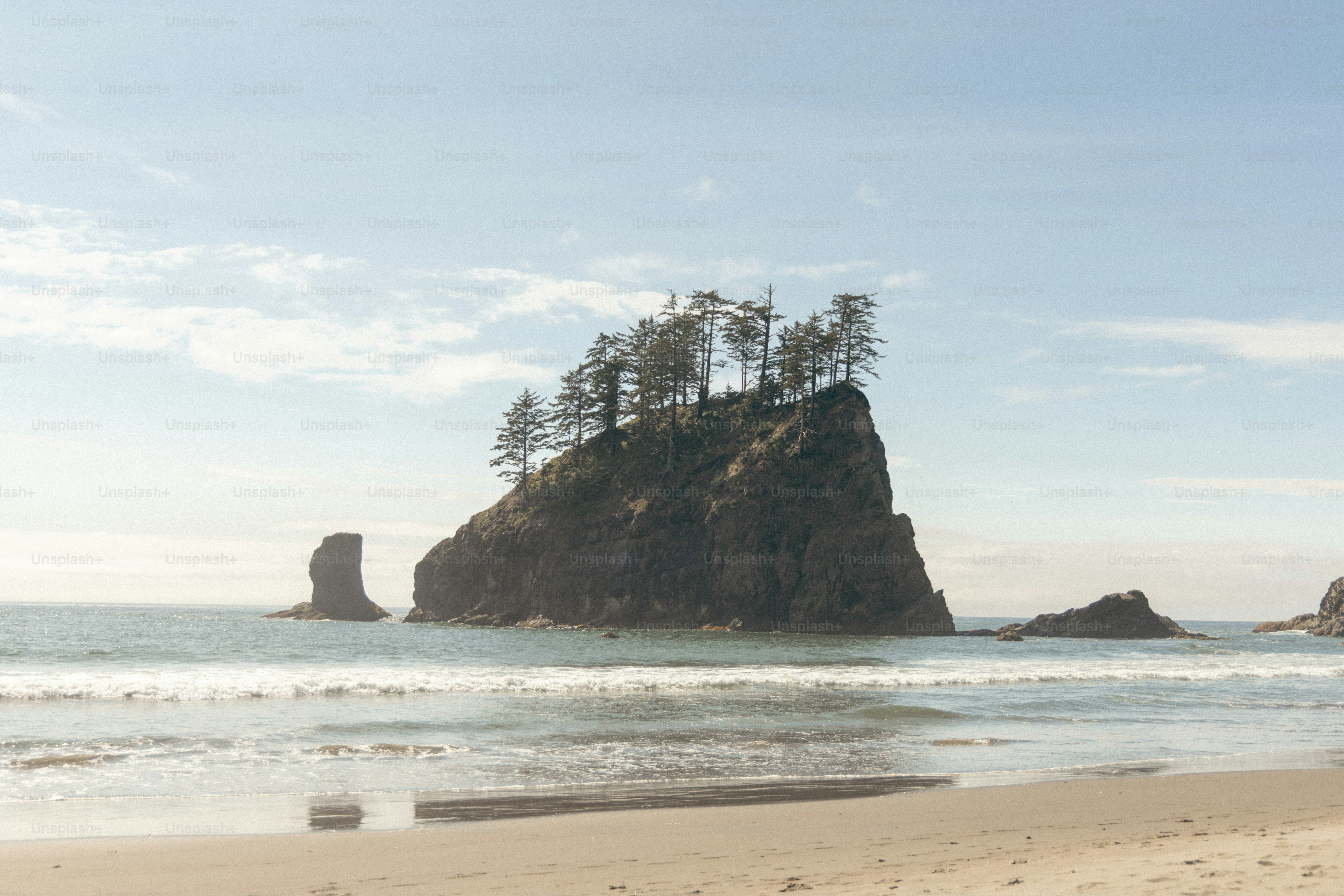 Una playa de arena con una formación rocosa a lo lejos foto – Imagen de ...