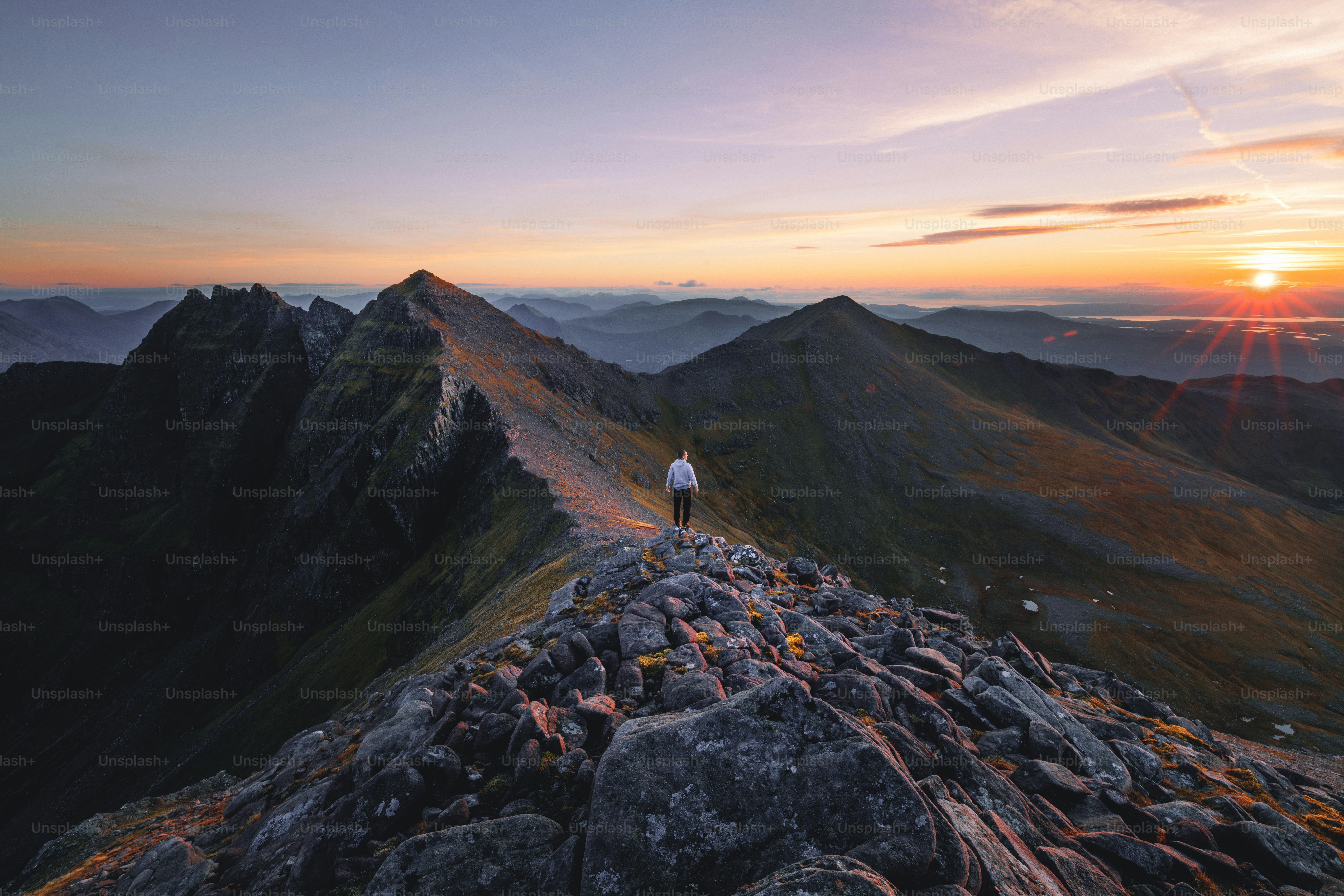 Una persona in piedi sulla cima di una montagna al tramonto foto ...