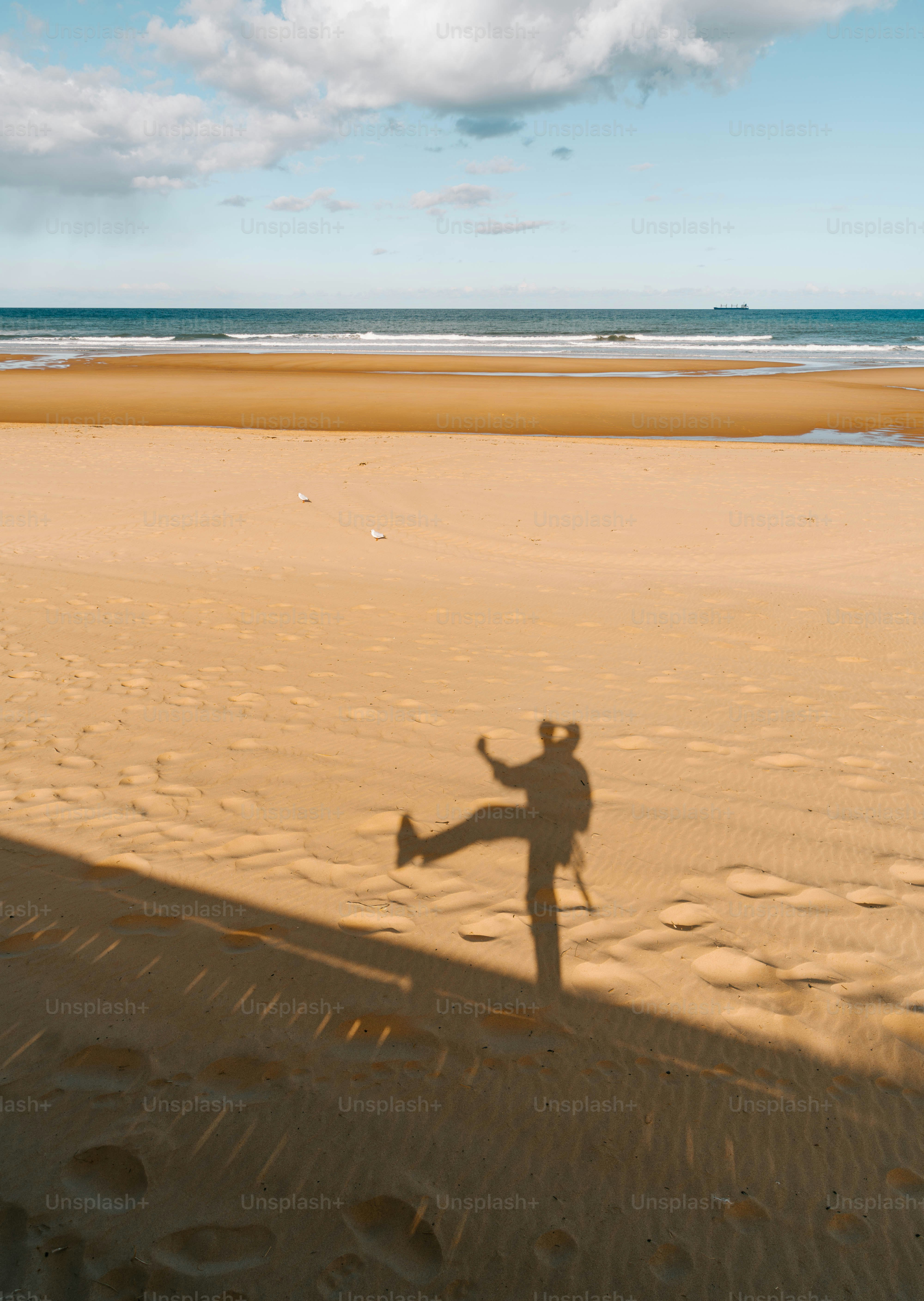 A shadow of a man kicking a soccer ball on a beach photo – Flash Image ...