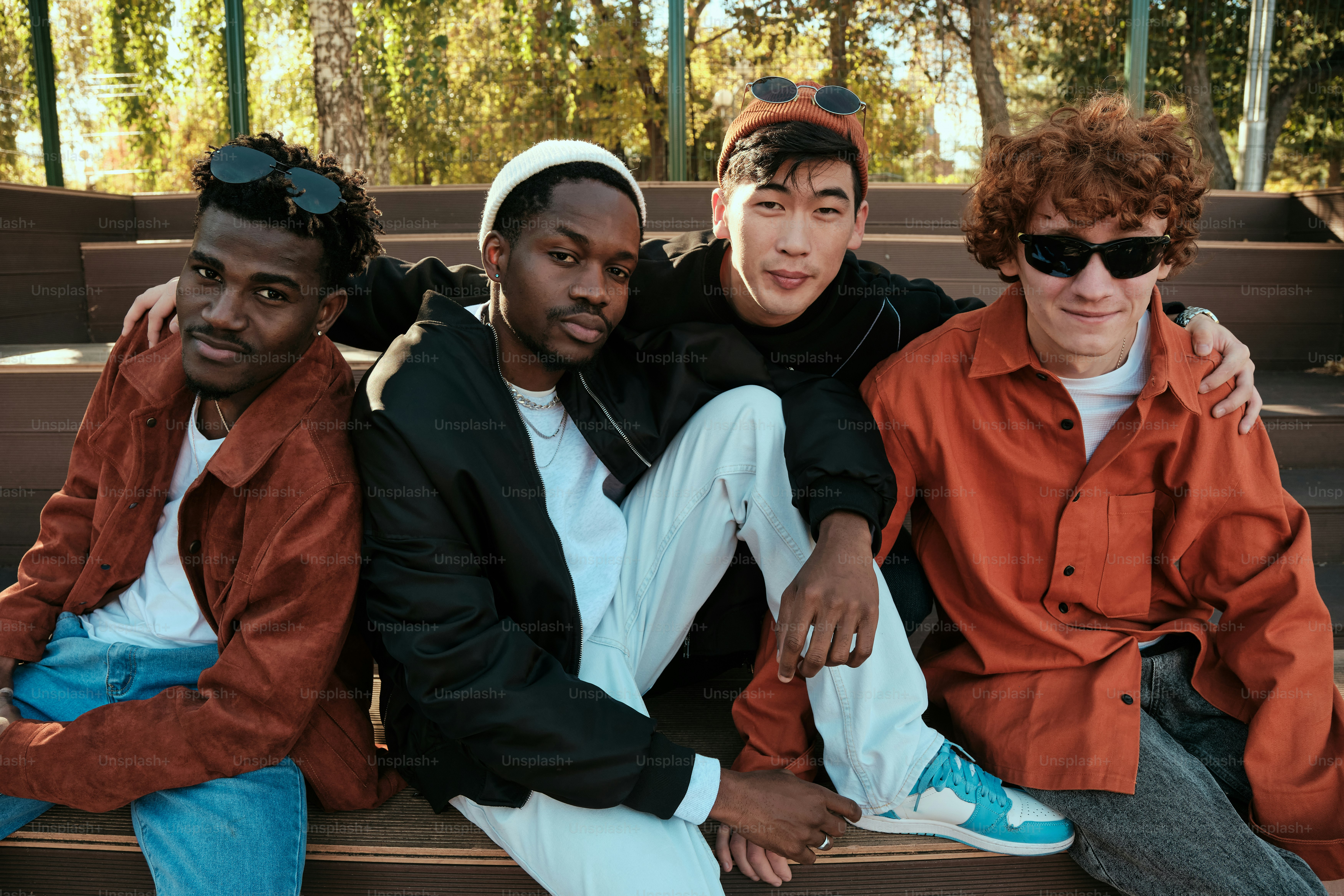 A group of young men sitting on top of a wooden bench photo ...