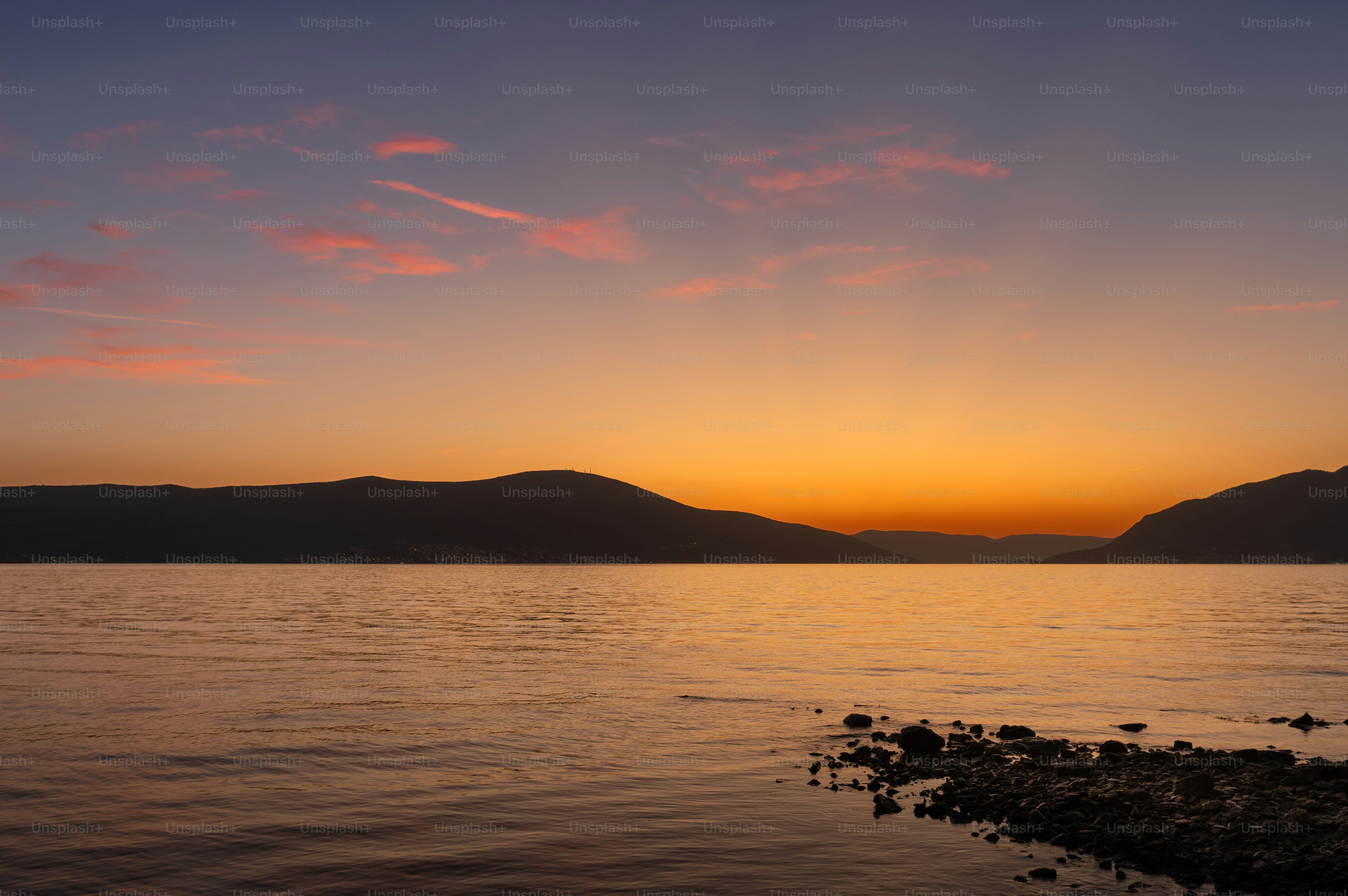 A sunset over a lake with mountains in the background photo – Sunset ...