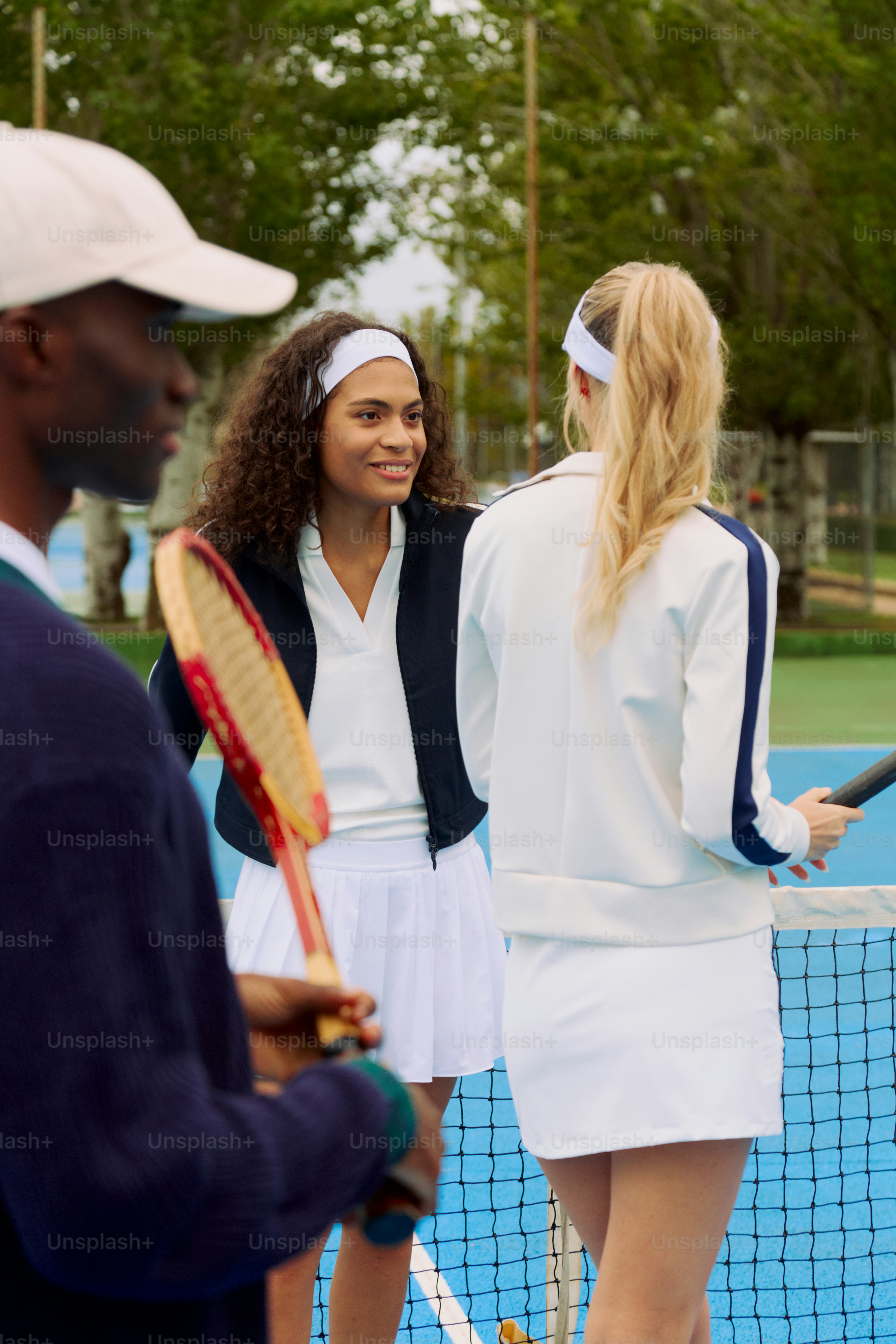 A group of people standing on a tennis court holding racquets photo ...