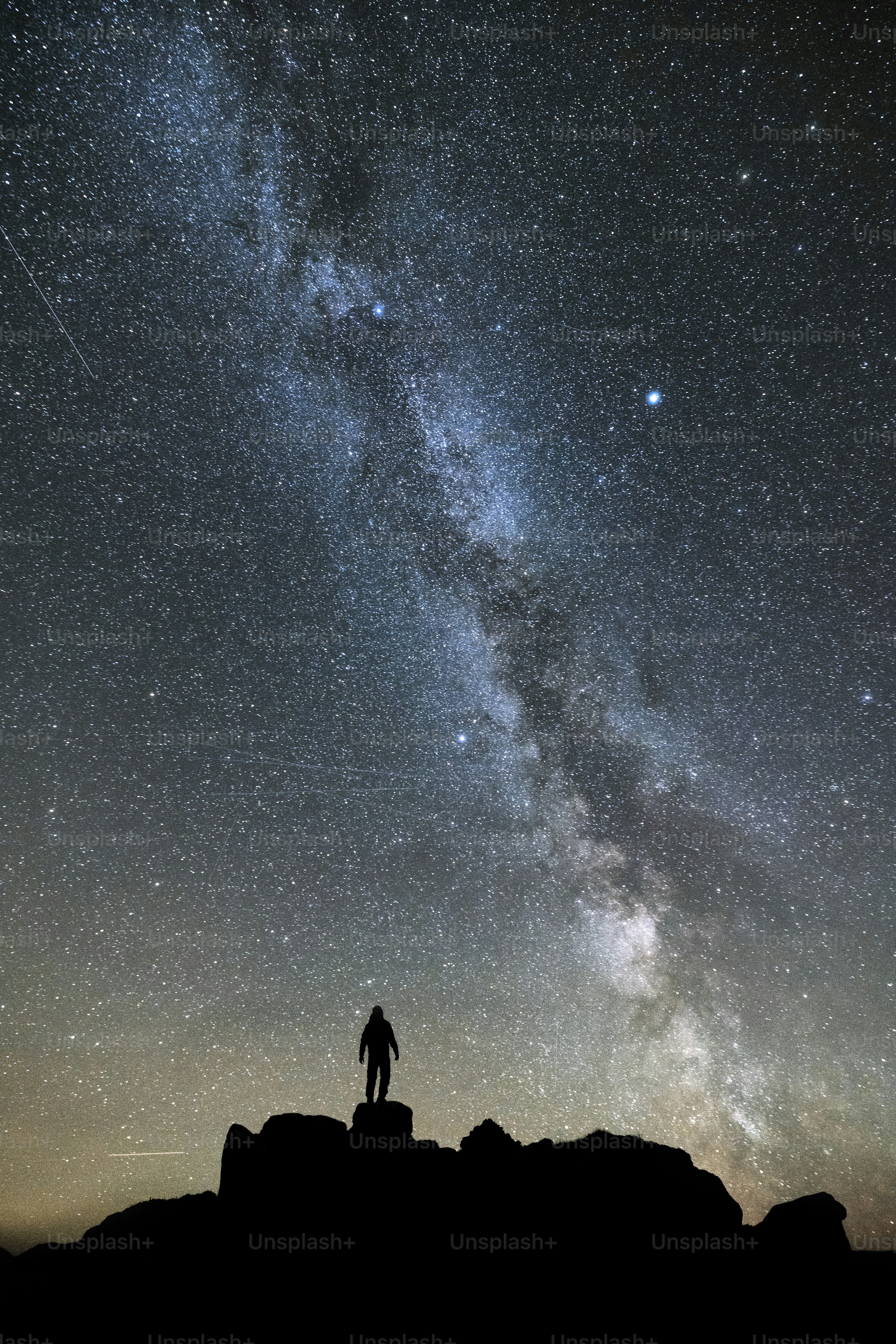 Una persona de pie en la cima de una montaña bajo un cielo lleno de ...