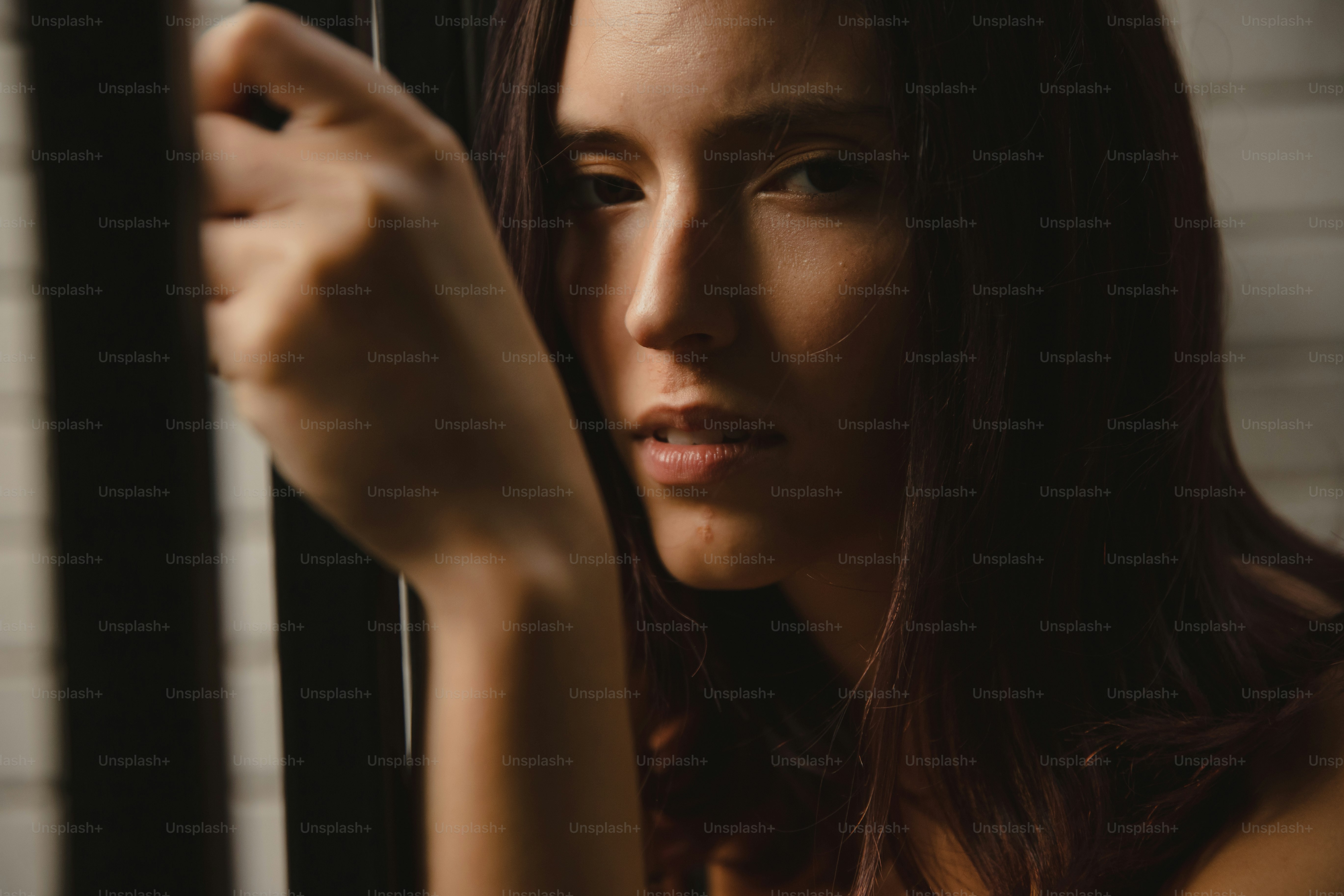 A woman looking out a window with her hand on the window sill photo ...