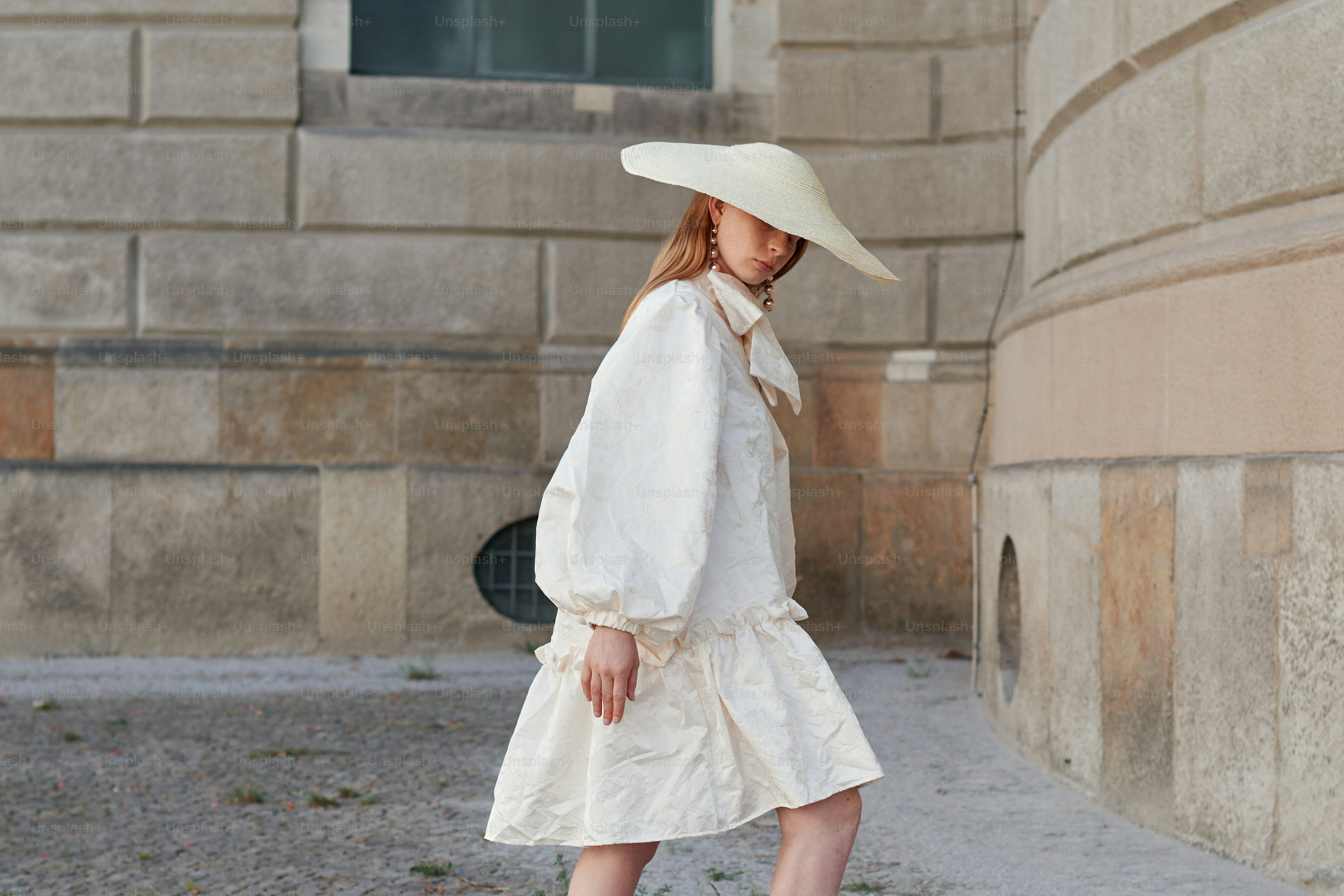 A woman wearing a large white hat on top of her head photo – Fashion ...