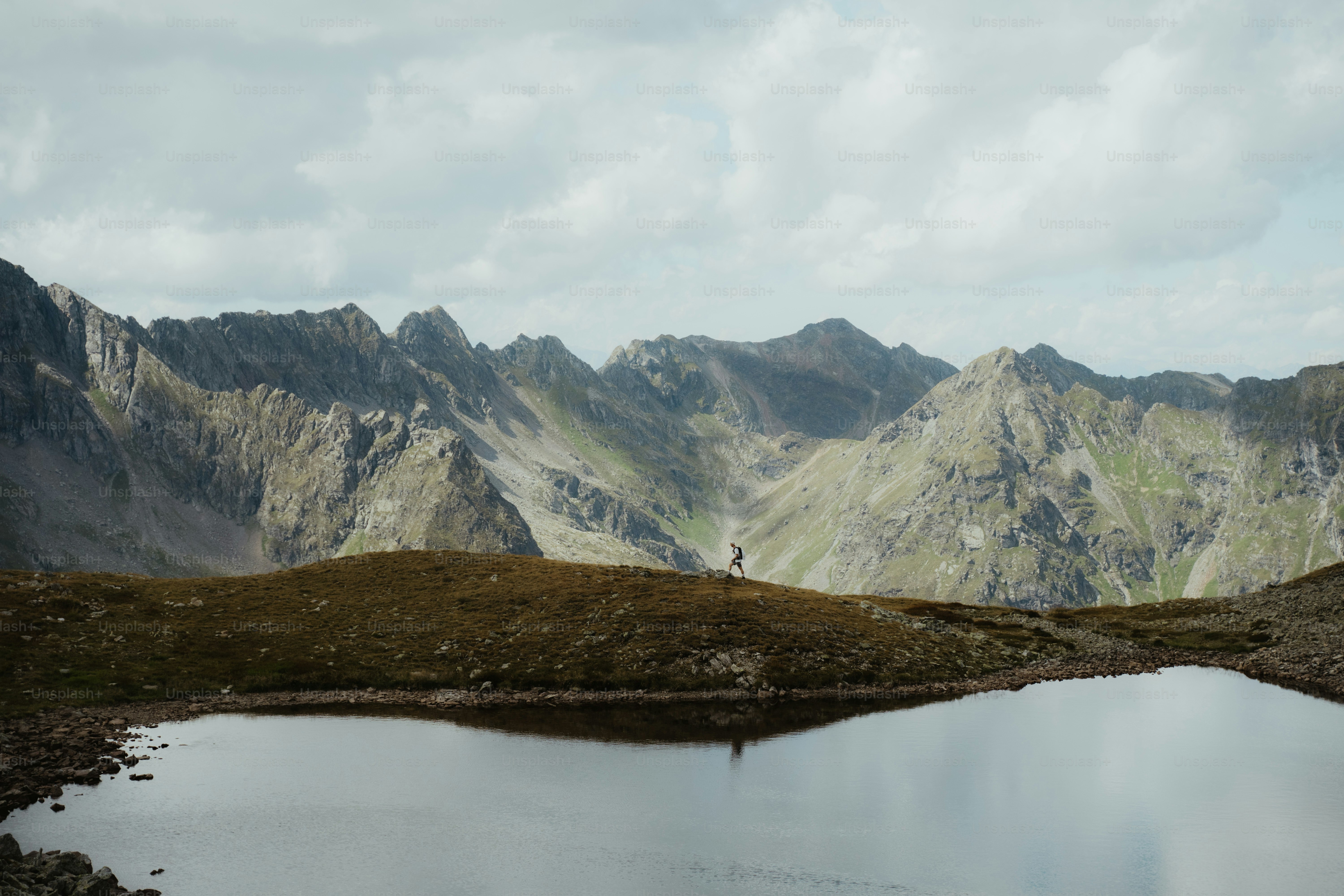 A small lake in the middle of a mountain range photo – Alone Image on ...