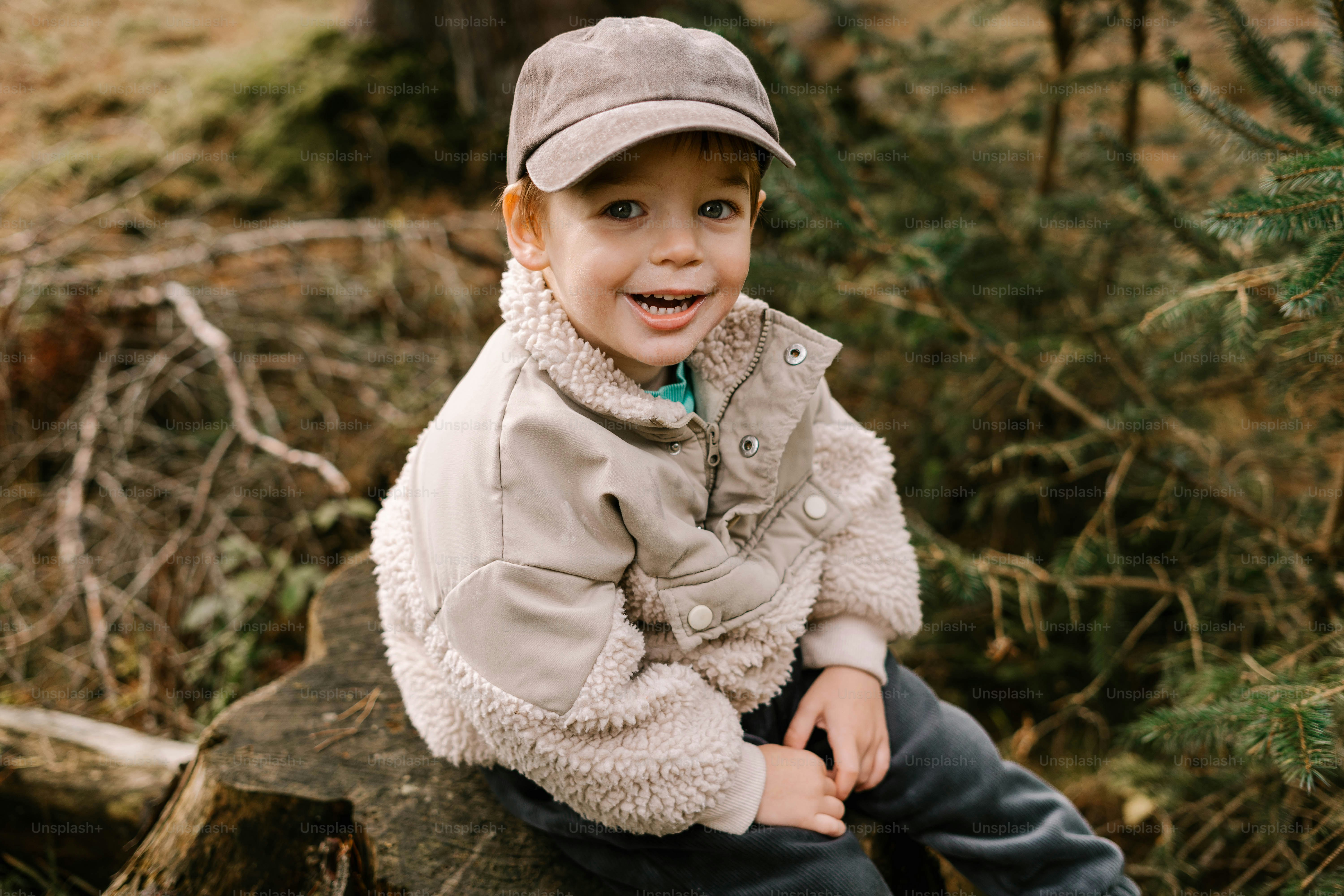 A little boy sitting on a bench in the woods photo – Small boy Image on ...