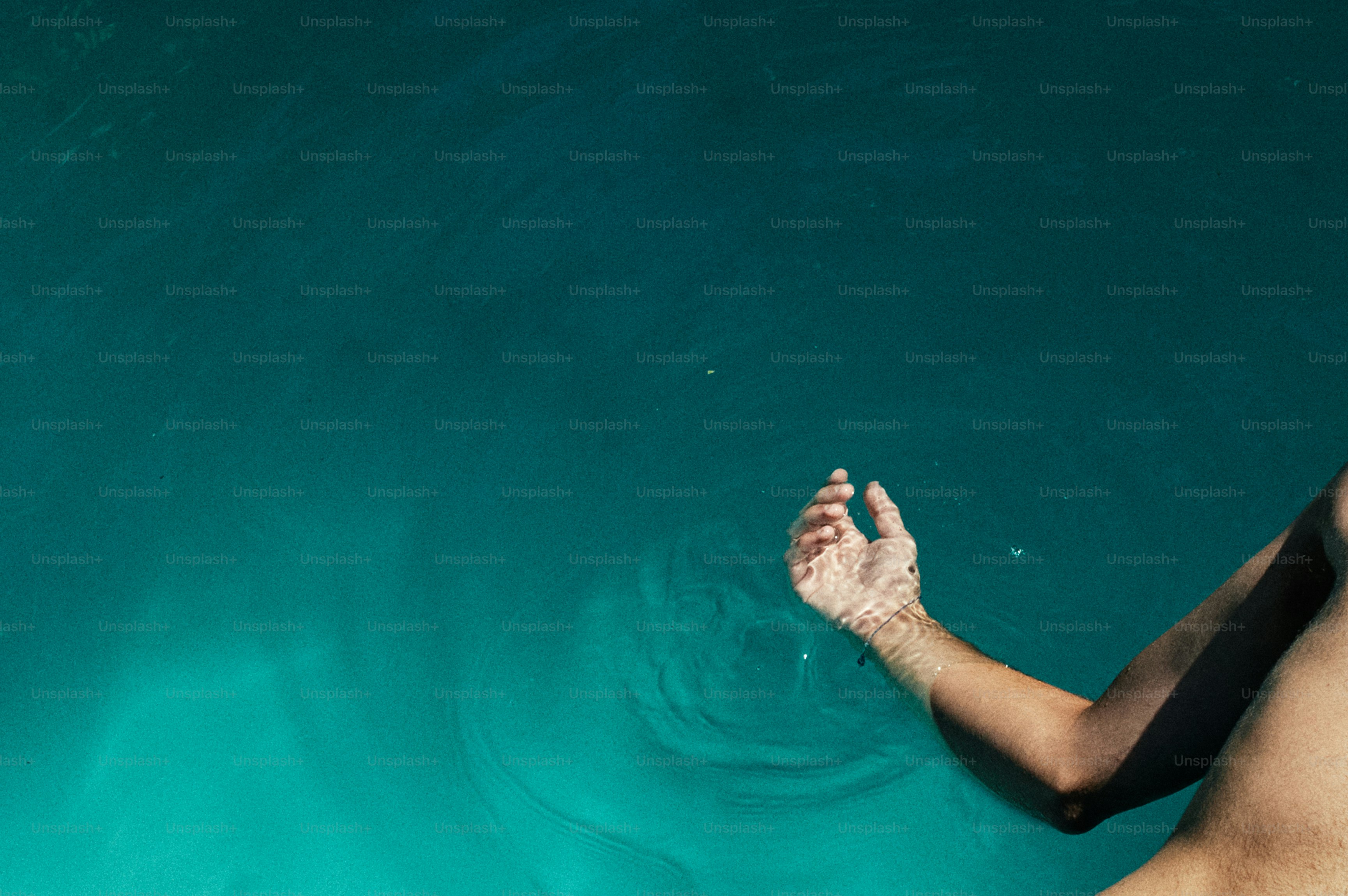 A man swimming in a pool with his hand in the water photo – Human body ...