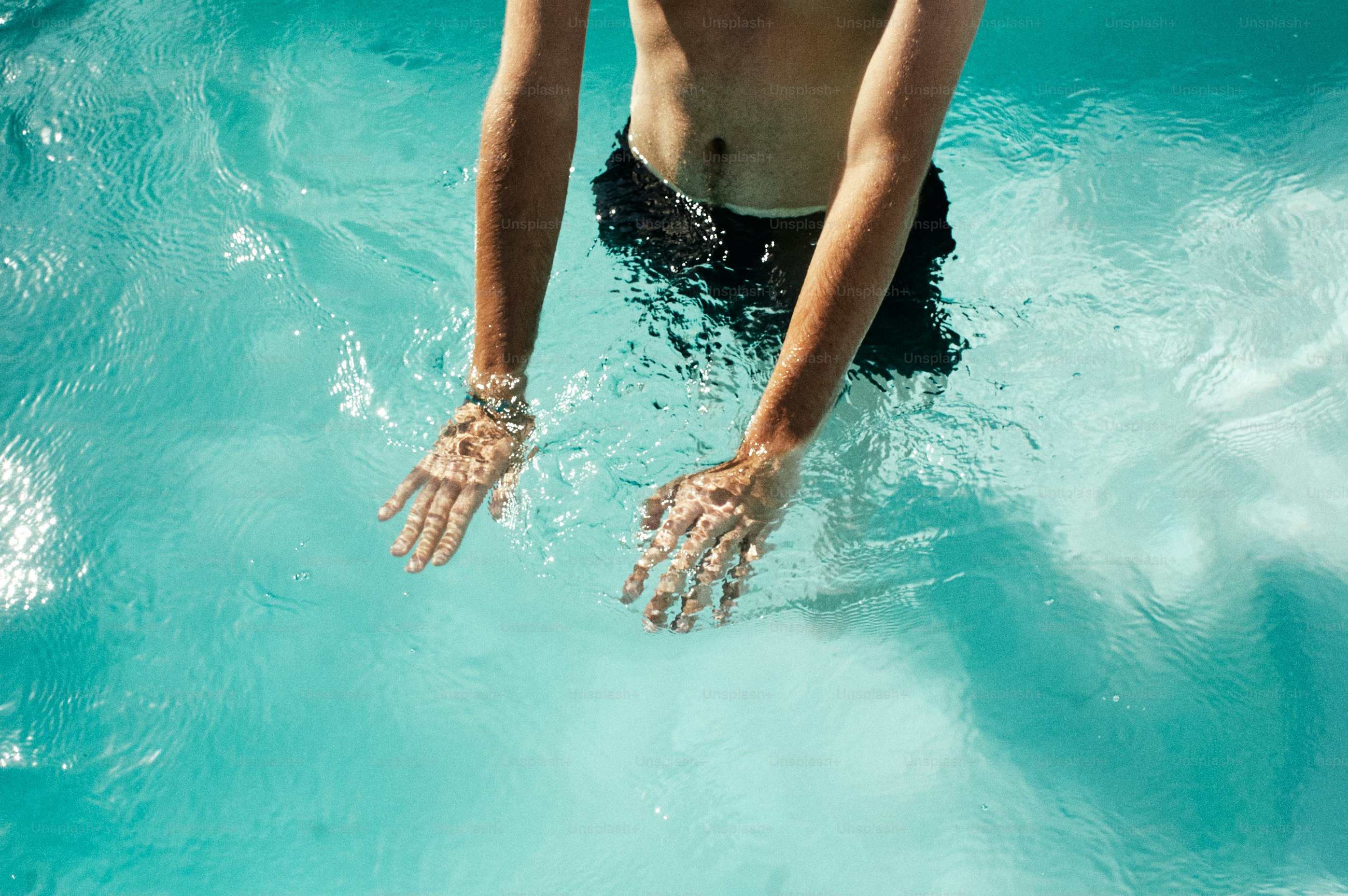 A man in a swimming pool with his hands in the water photo – Hand Image ...