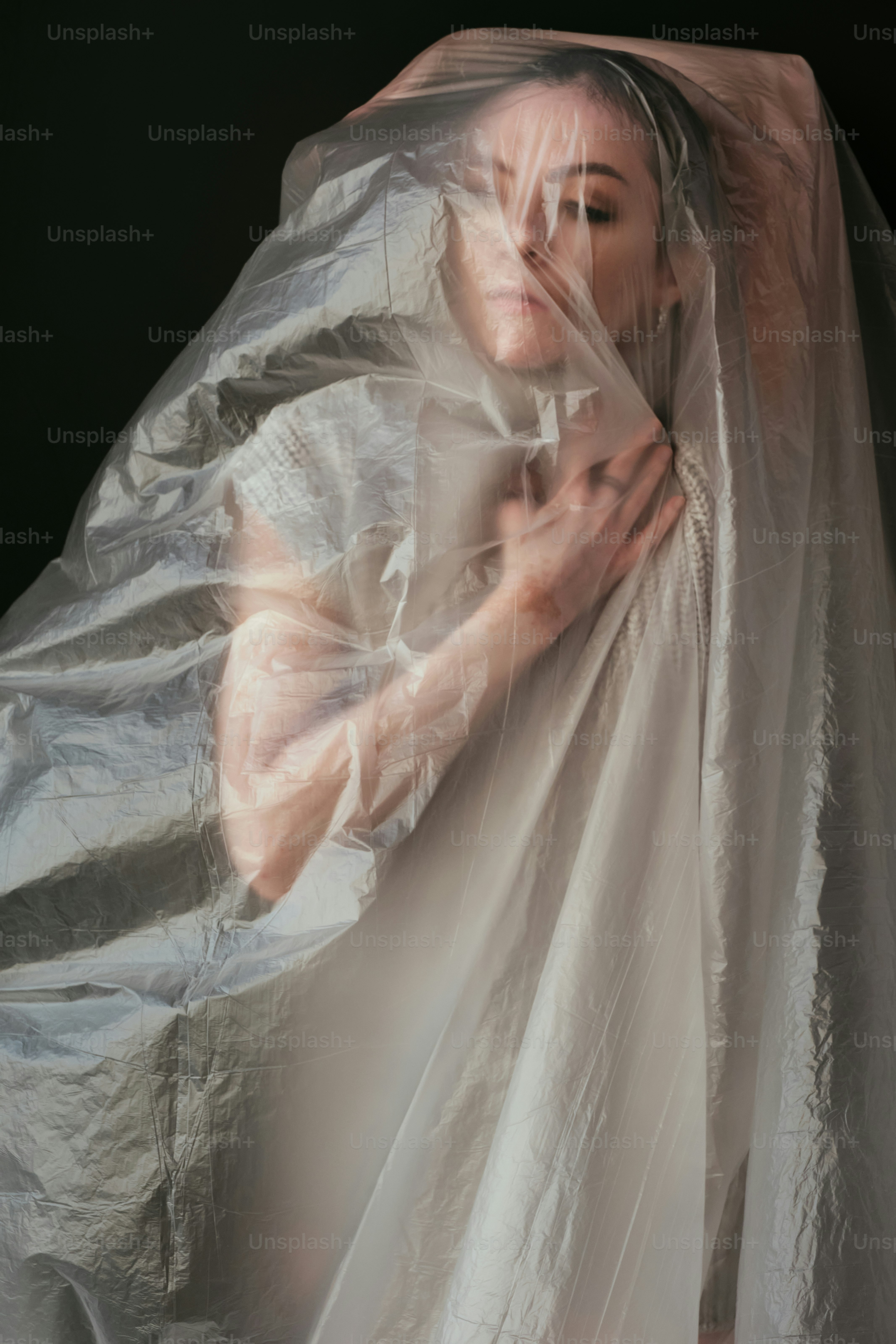 A woman wrapped in plastic covering herself with a sheet photo ...
