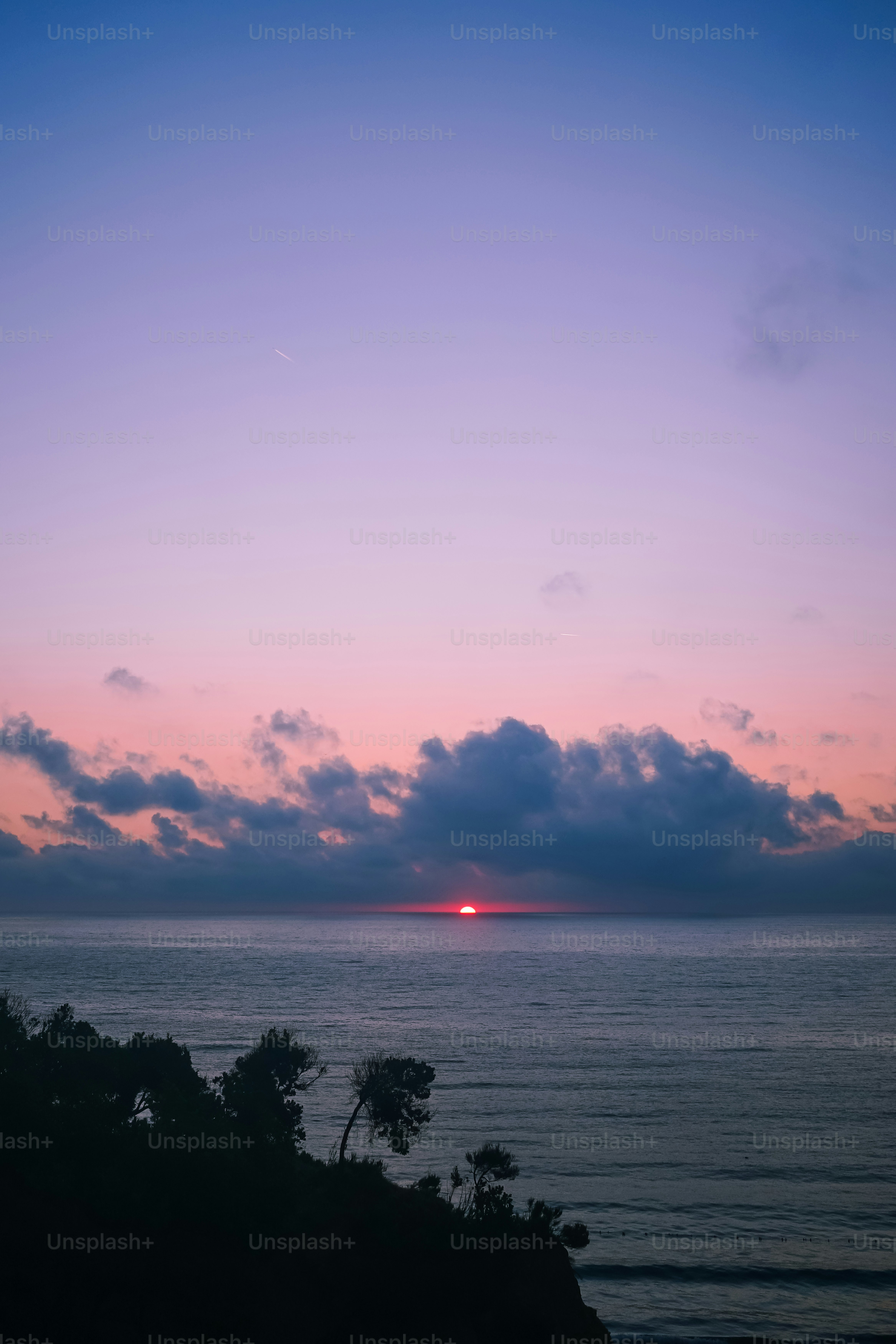 The sun is setting over the ocean on a cloudy day photo – Sunset Image ...