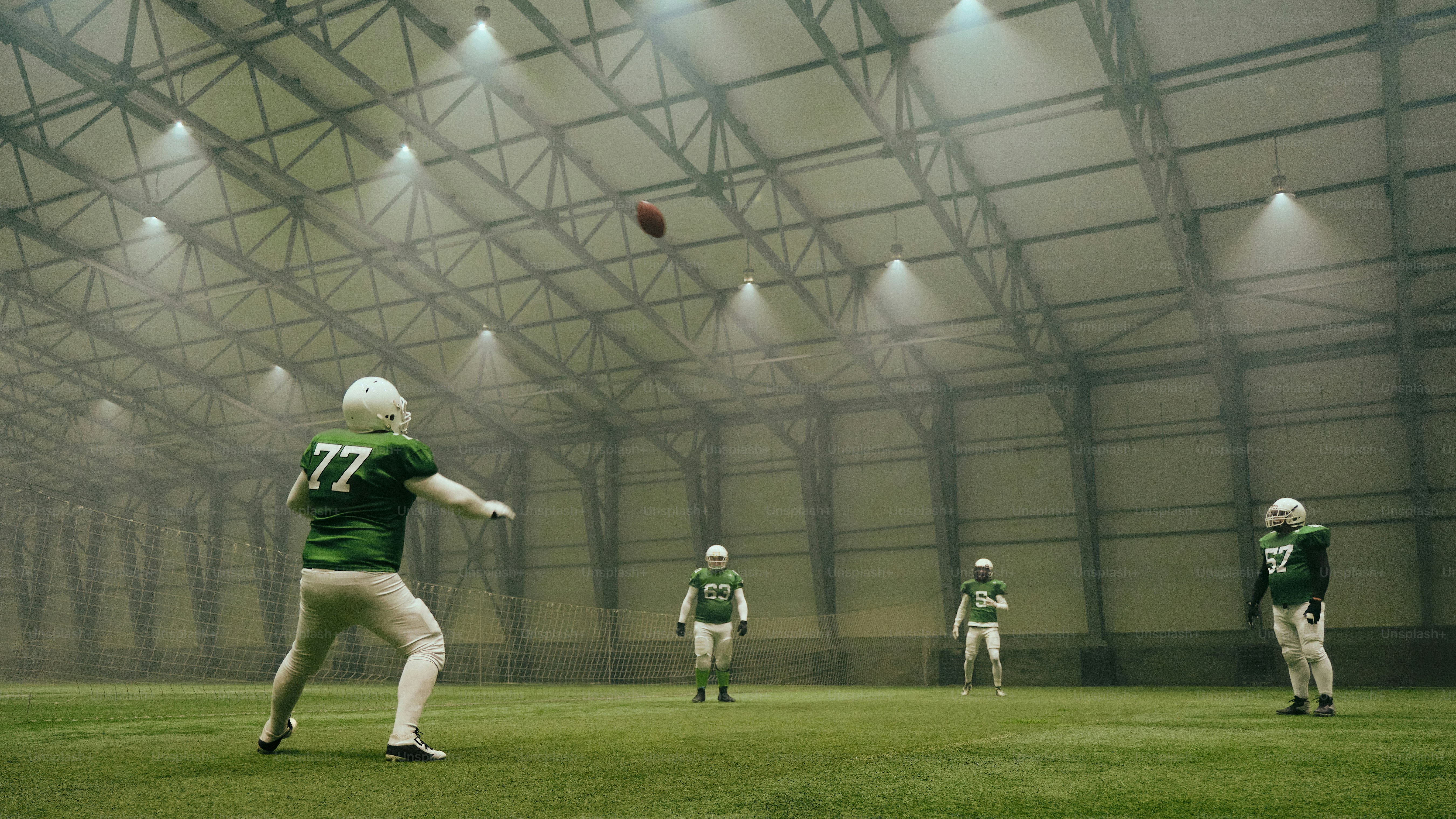 A group of football players standing on top of a field photo – Team ...