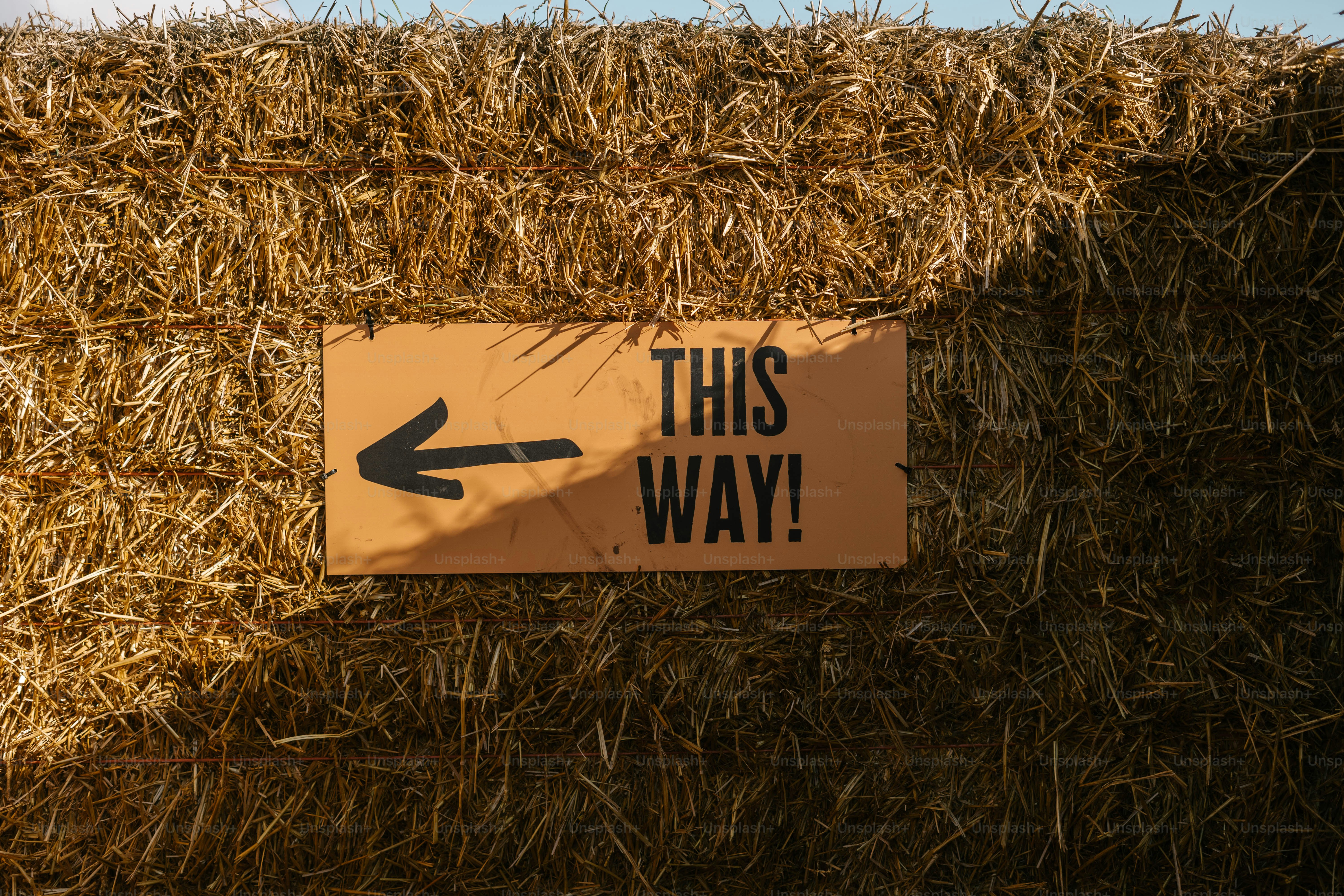 A sign on a pile of hay that says this way photo – Hay bales Image on ...