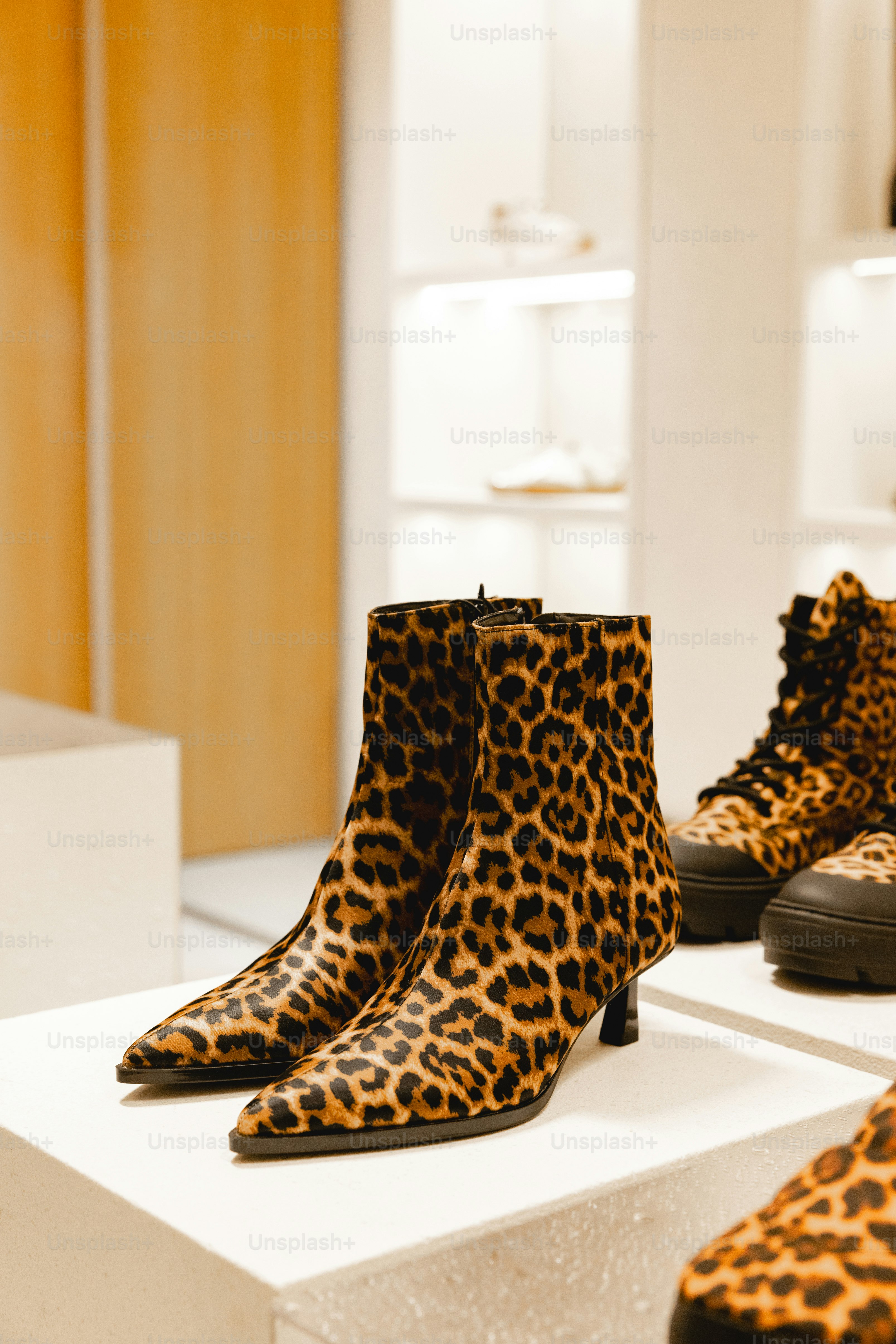 A pair of leopard print boots sitting on top of a white platform photo ...