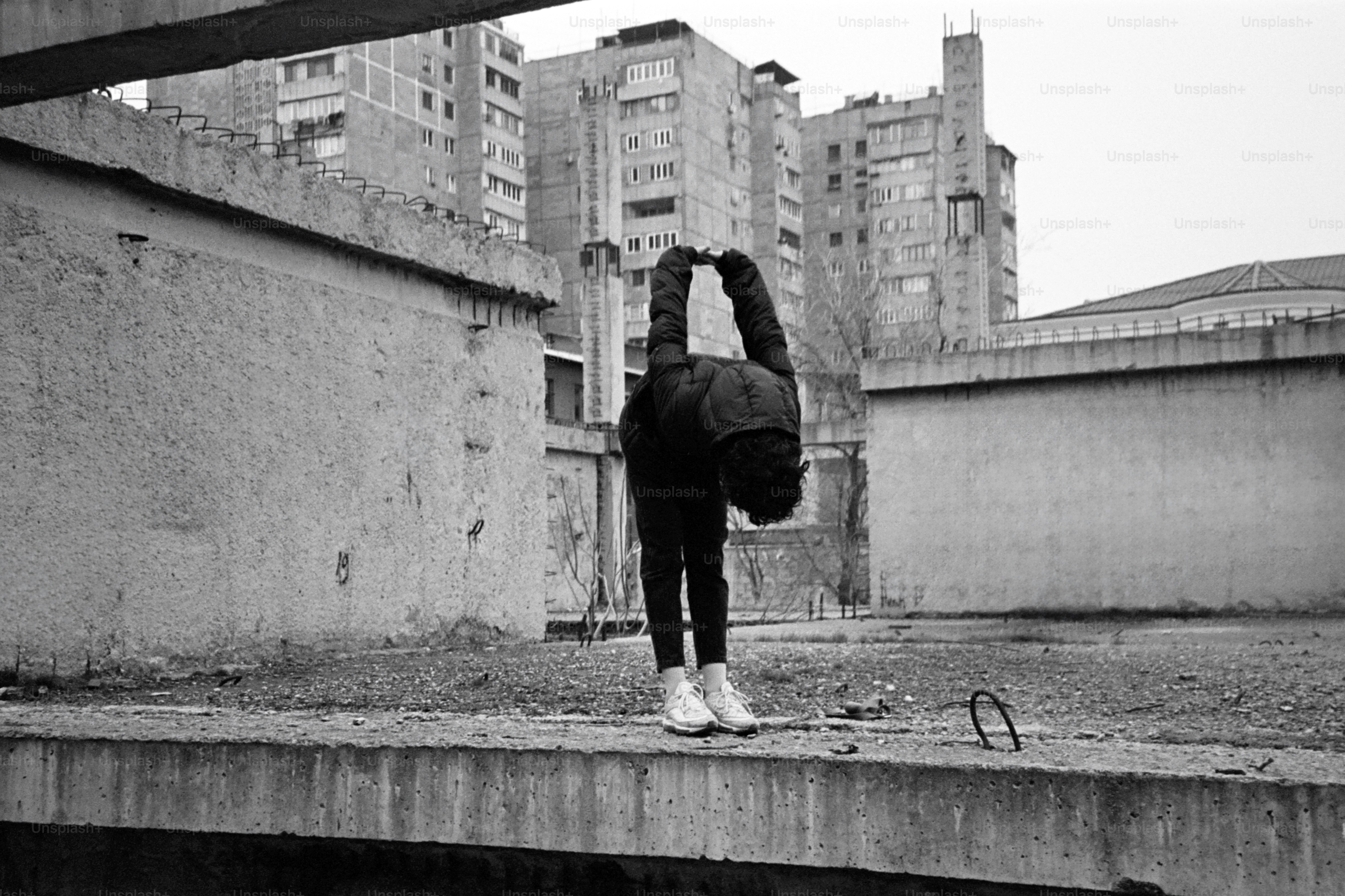 A person standing on a ledge with their hands in the air photo – Analog ...