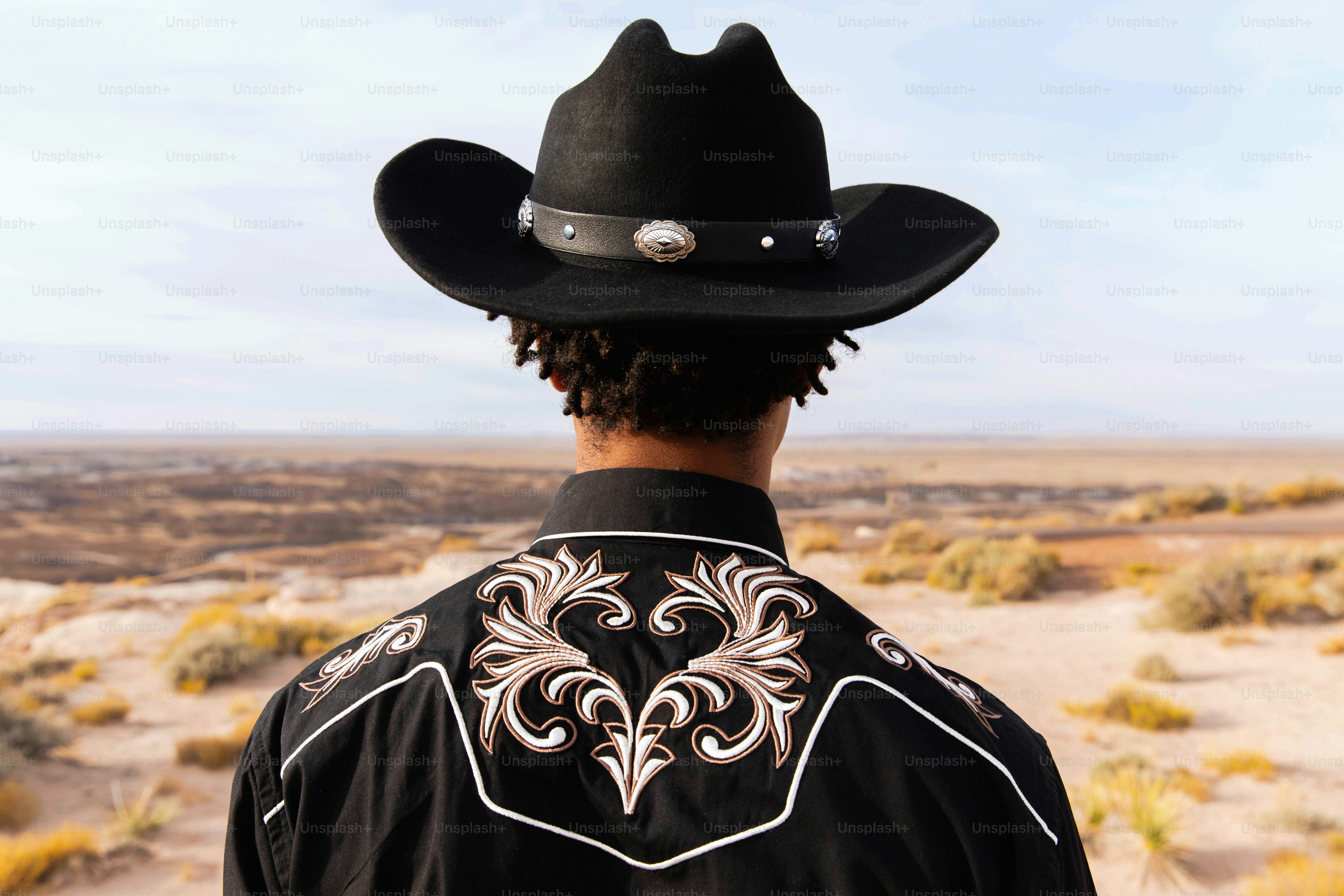 A man in a cowboy hat looking out over the desert photo – Looking at ...