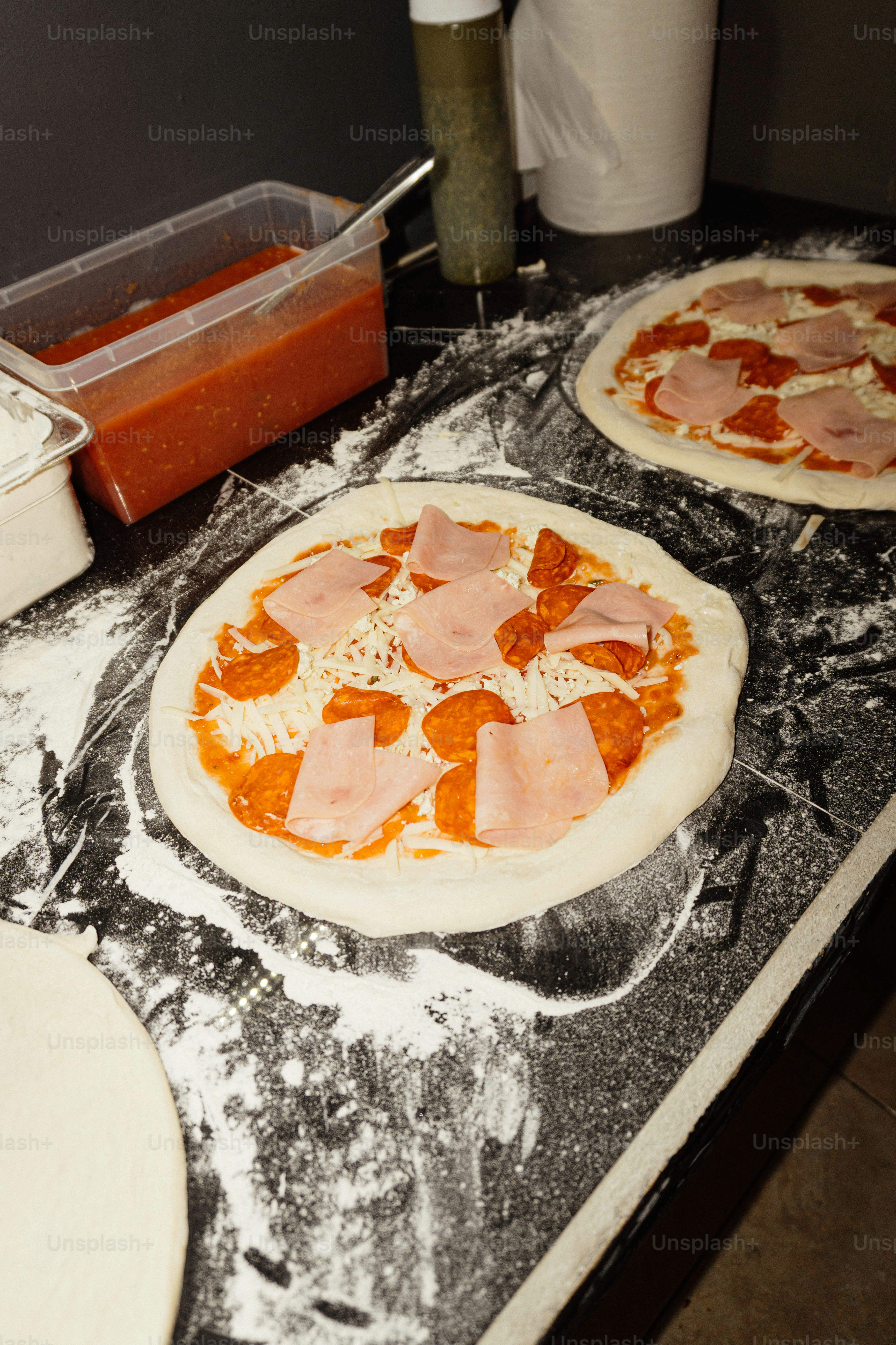 Two uncooked pizzas sitting on top of a counter photo – Pizza Image on ...