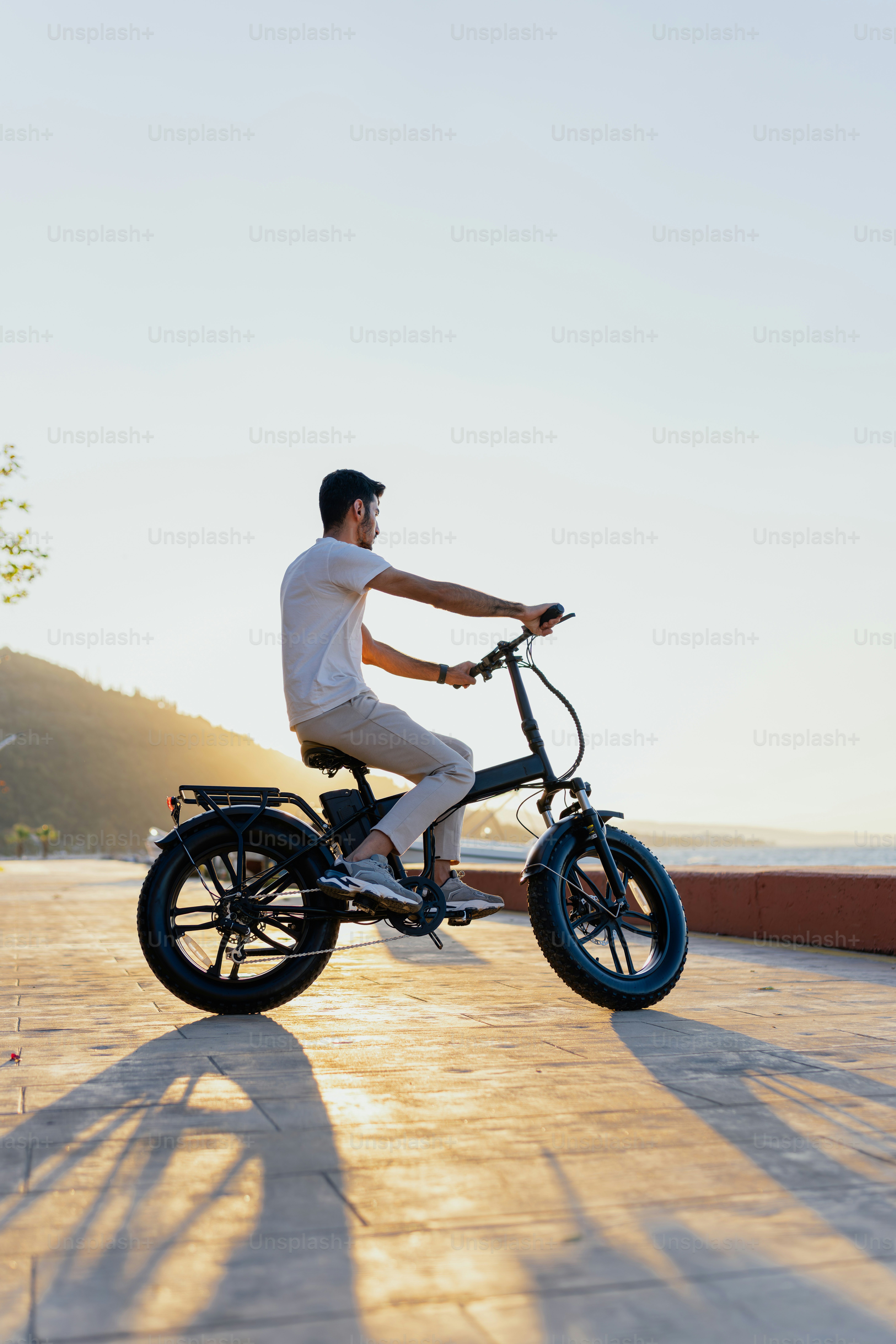 A man riding a bike down a sidewalk next to the ocean photo – Bike ...