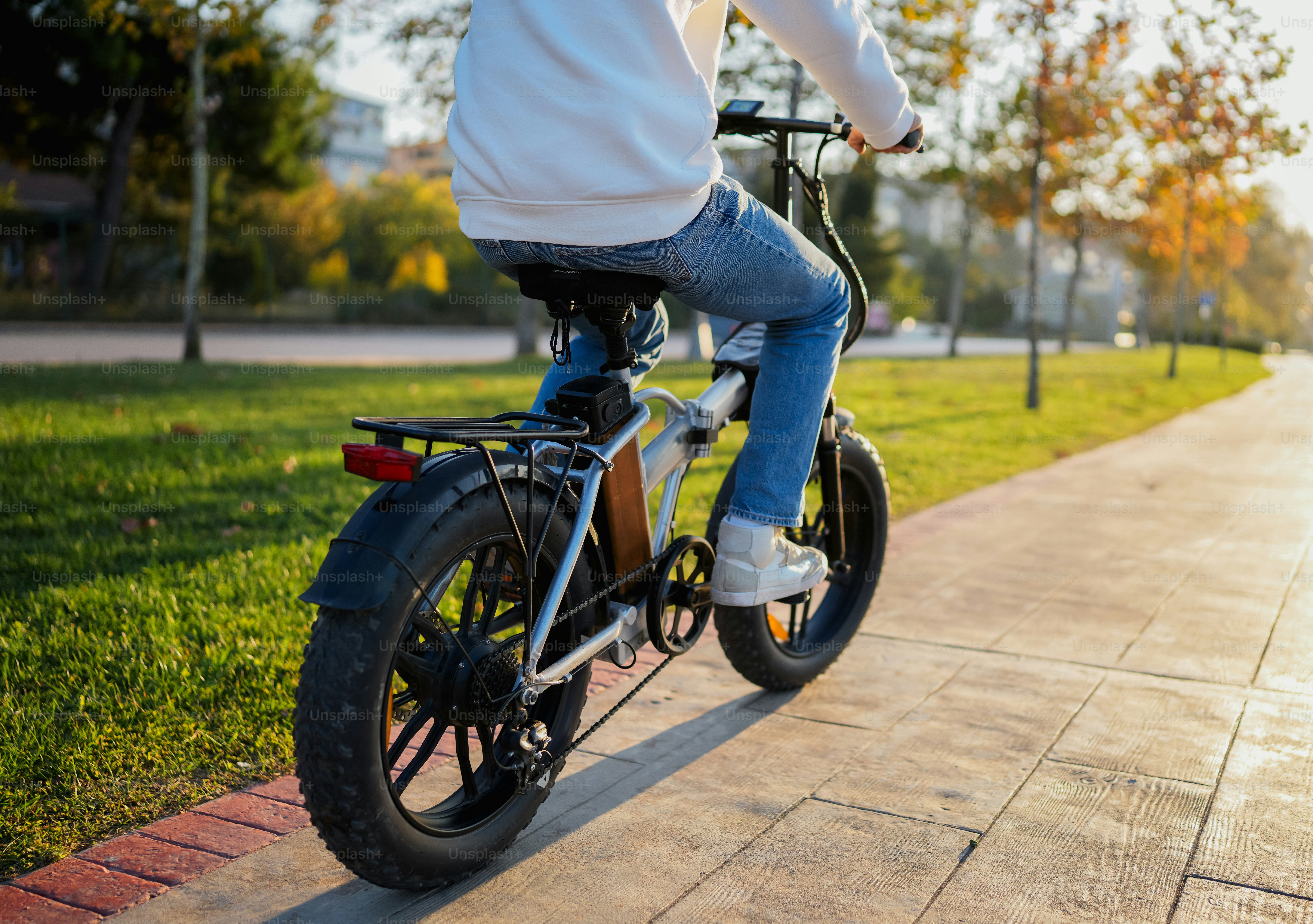 A man riding a bike down a sidewalk next to the ocean photo – Bike ...