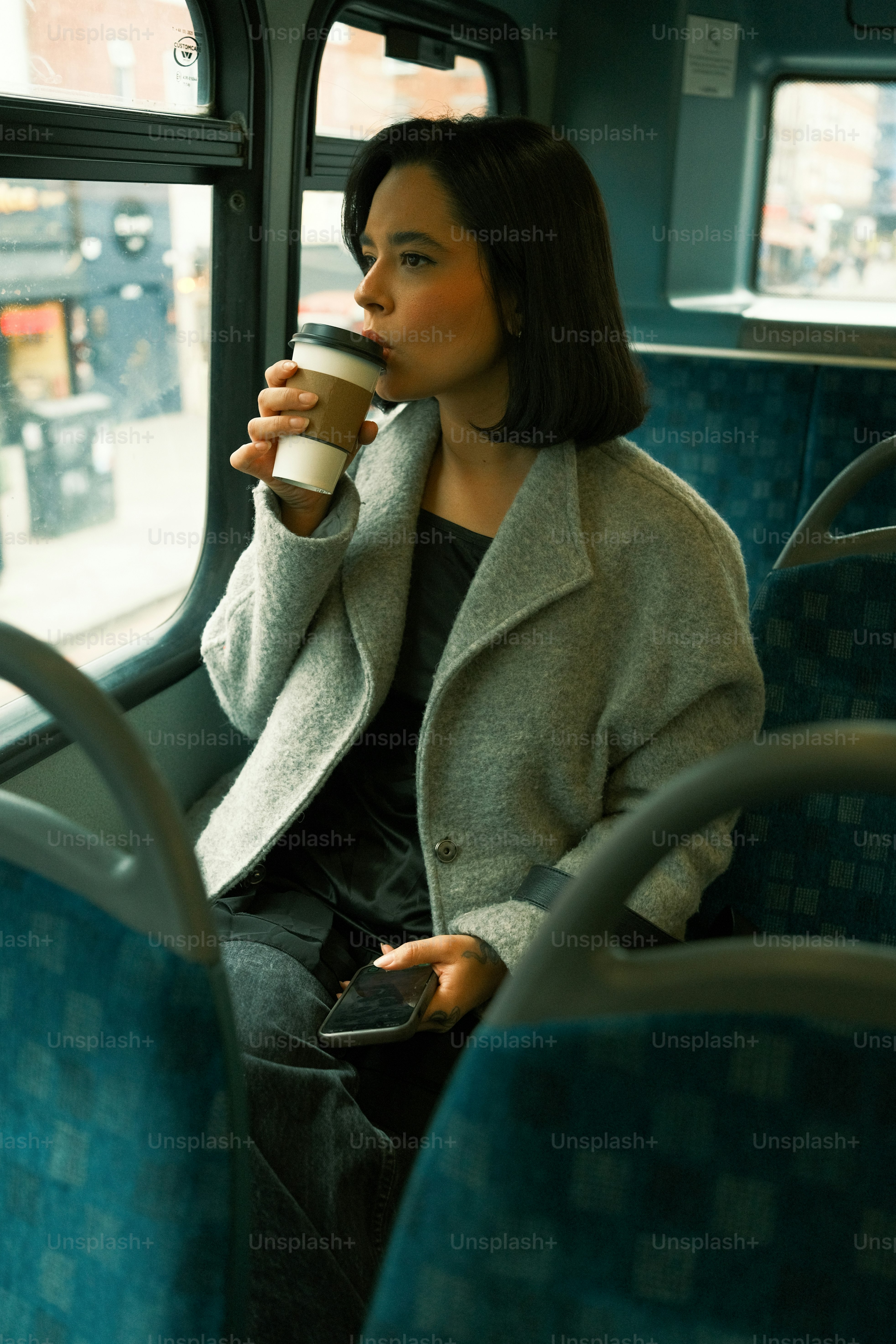A woman sitting on a bus drinking from a cup photo – Professional Image ...
