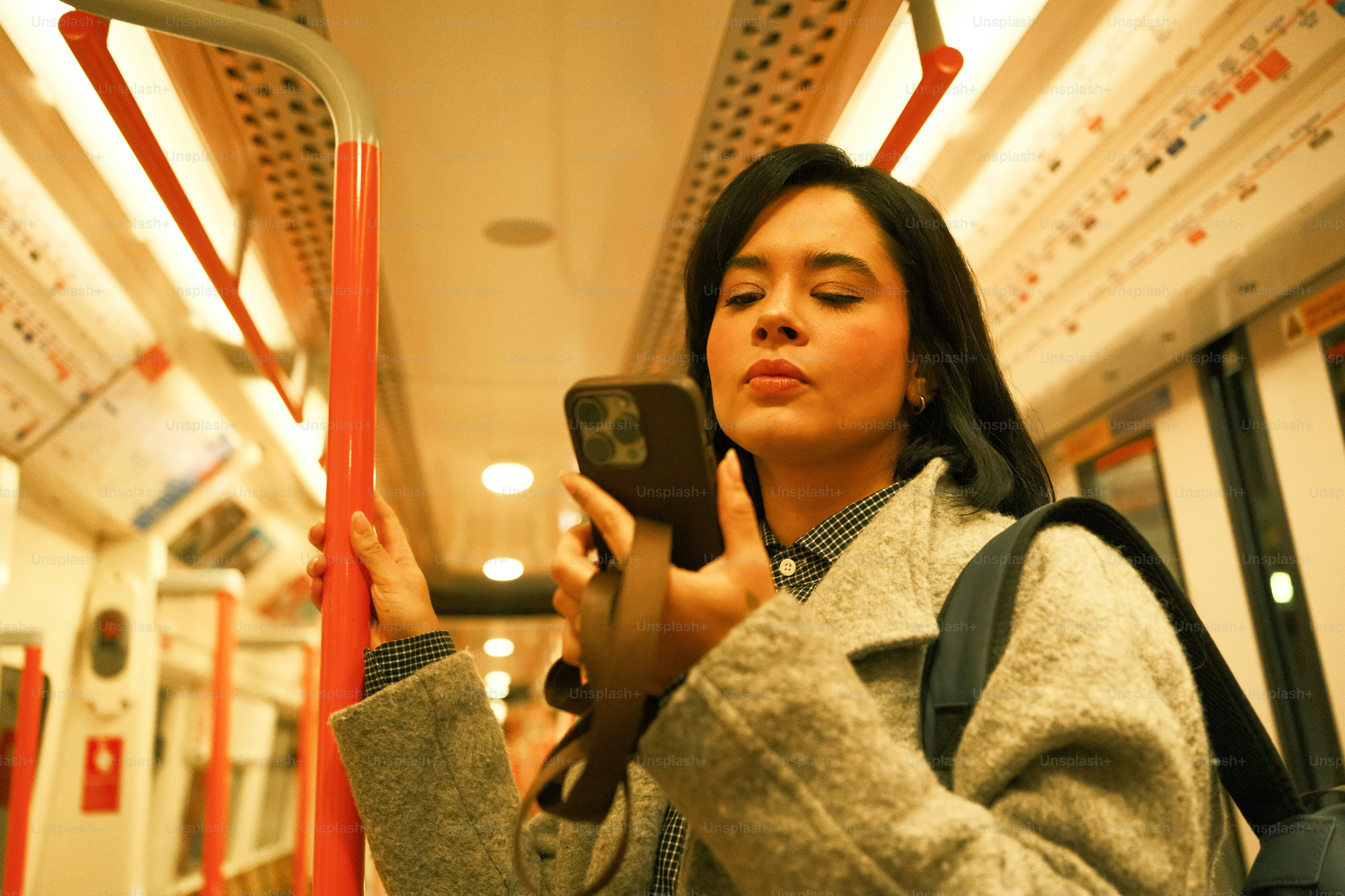A woman on a subway looking at her cell phone photo – Professional ...