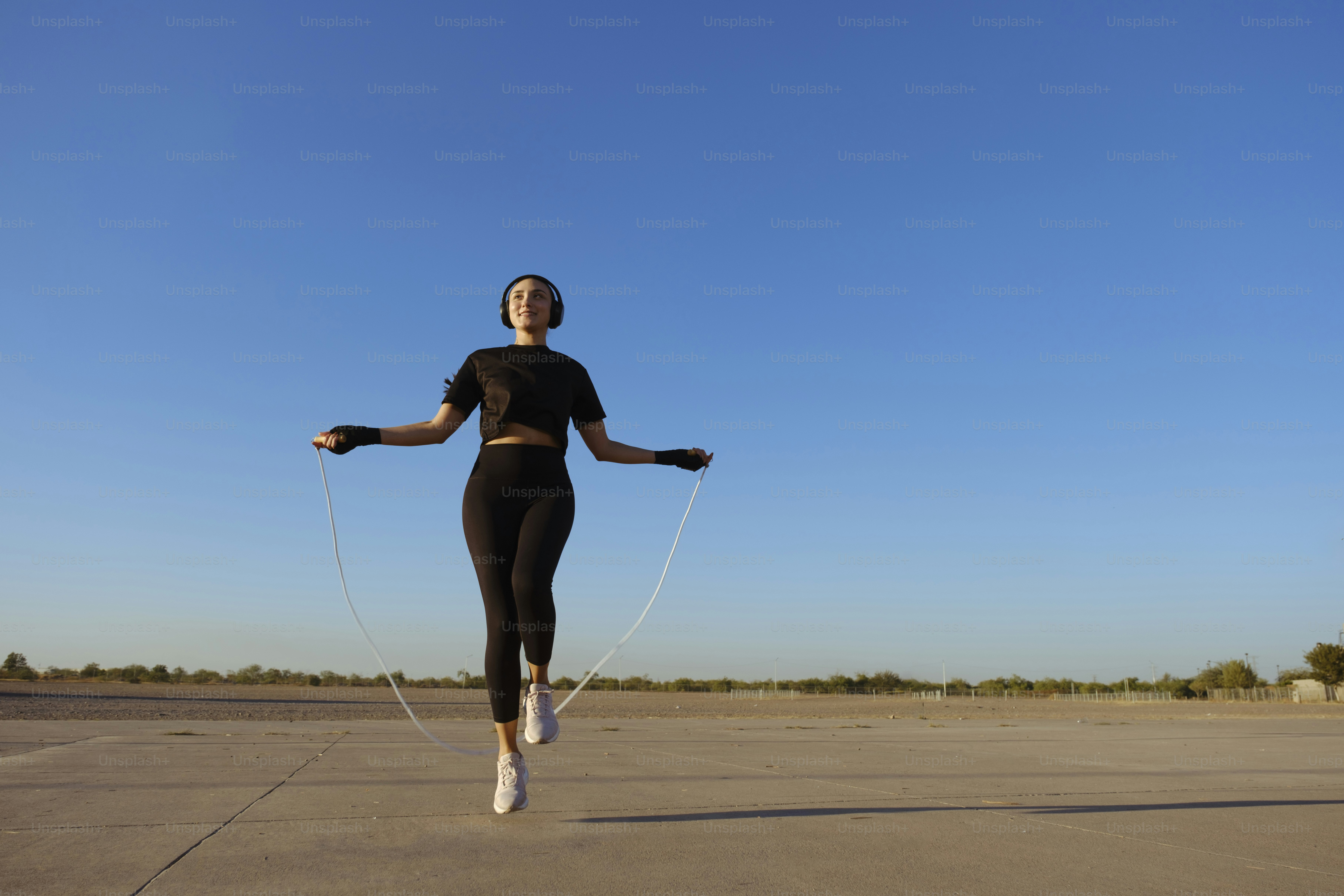A woman in a black top is running with a skipping rope photo – Musical ...