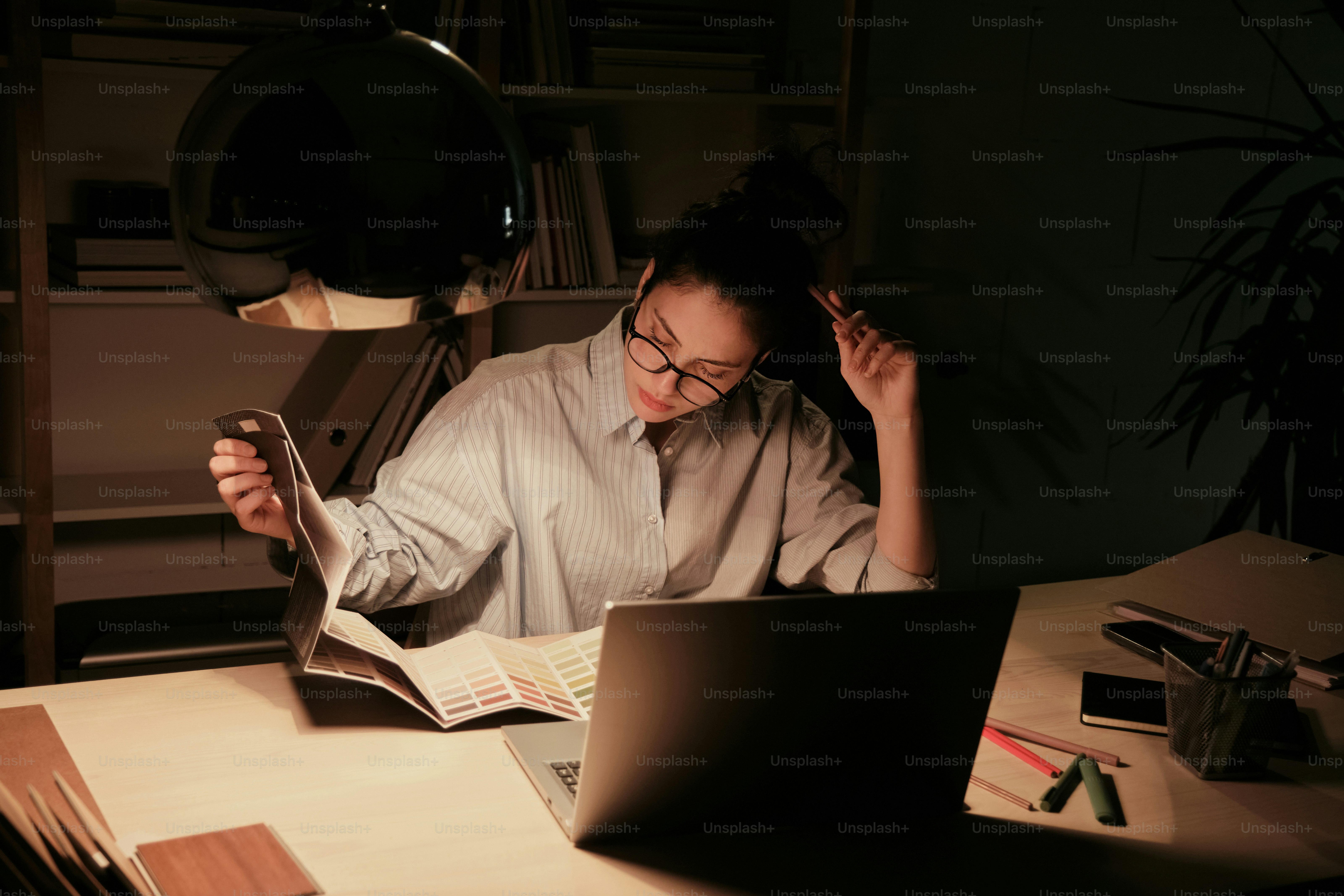 A woman sitting at a desk reading a book photo – Office Image on Unsplash
