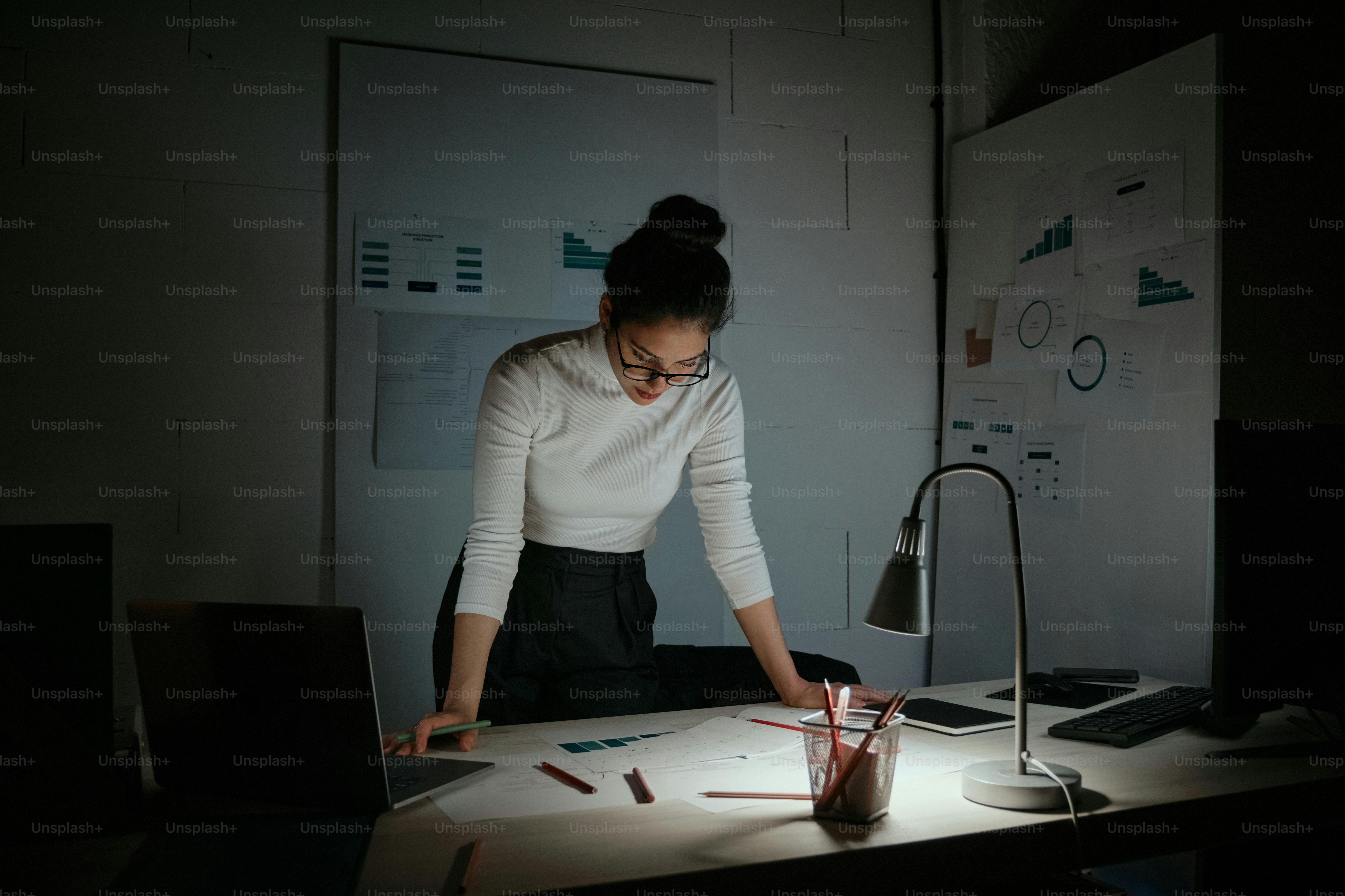 A woman standing at a desk in a dark room photo – Office Image on Unsplash