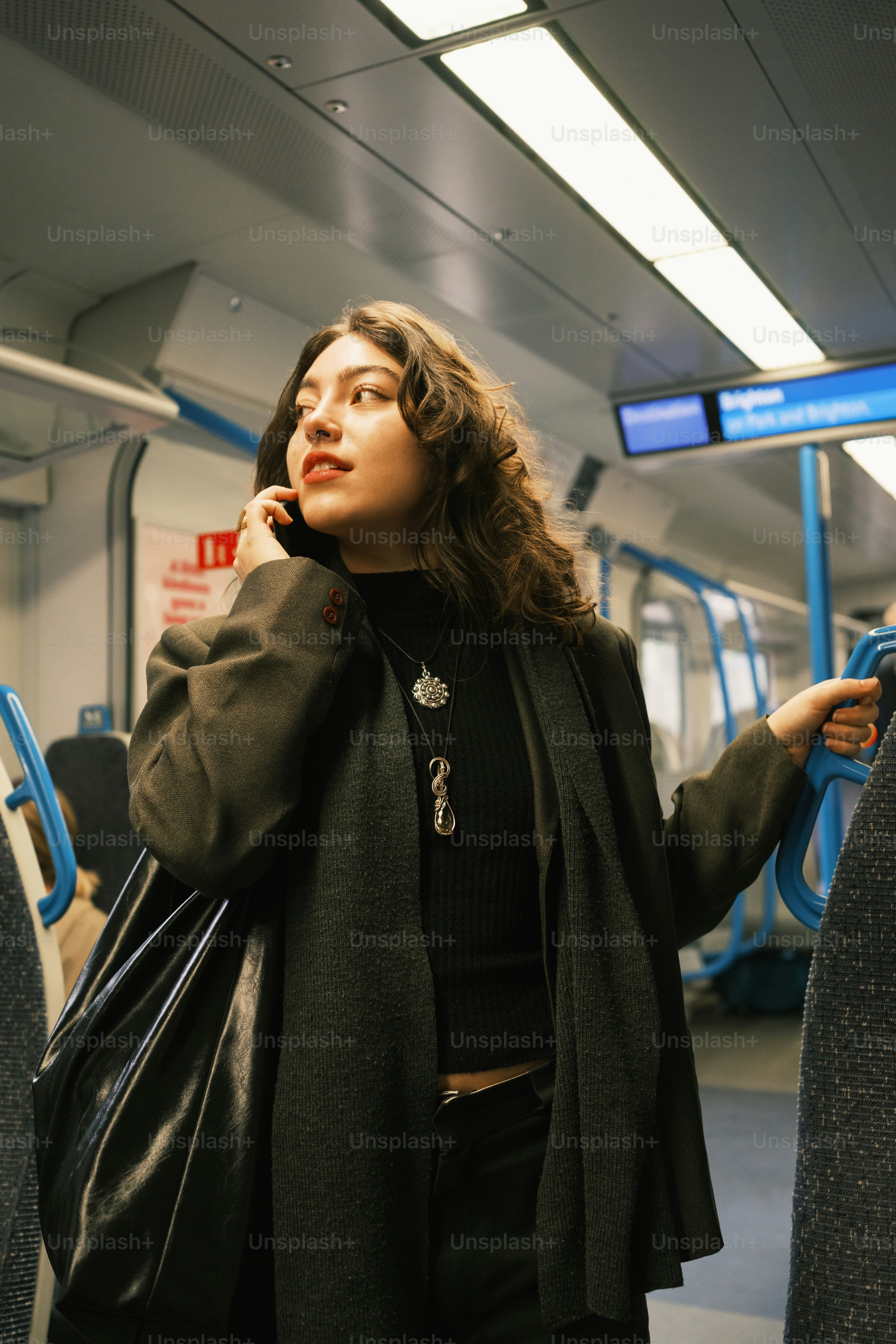 A woman standing on a subway train talking on a cell phone photo ...