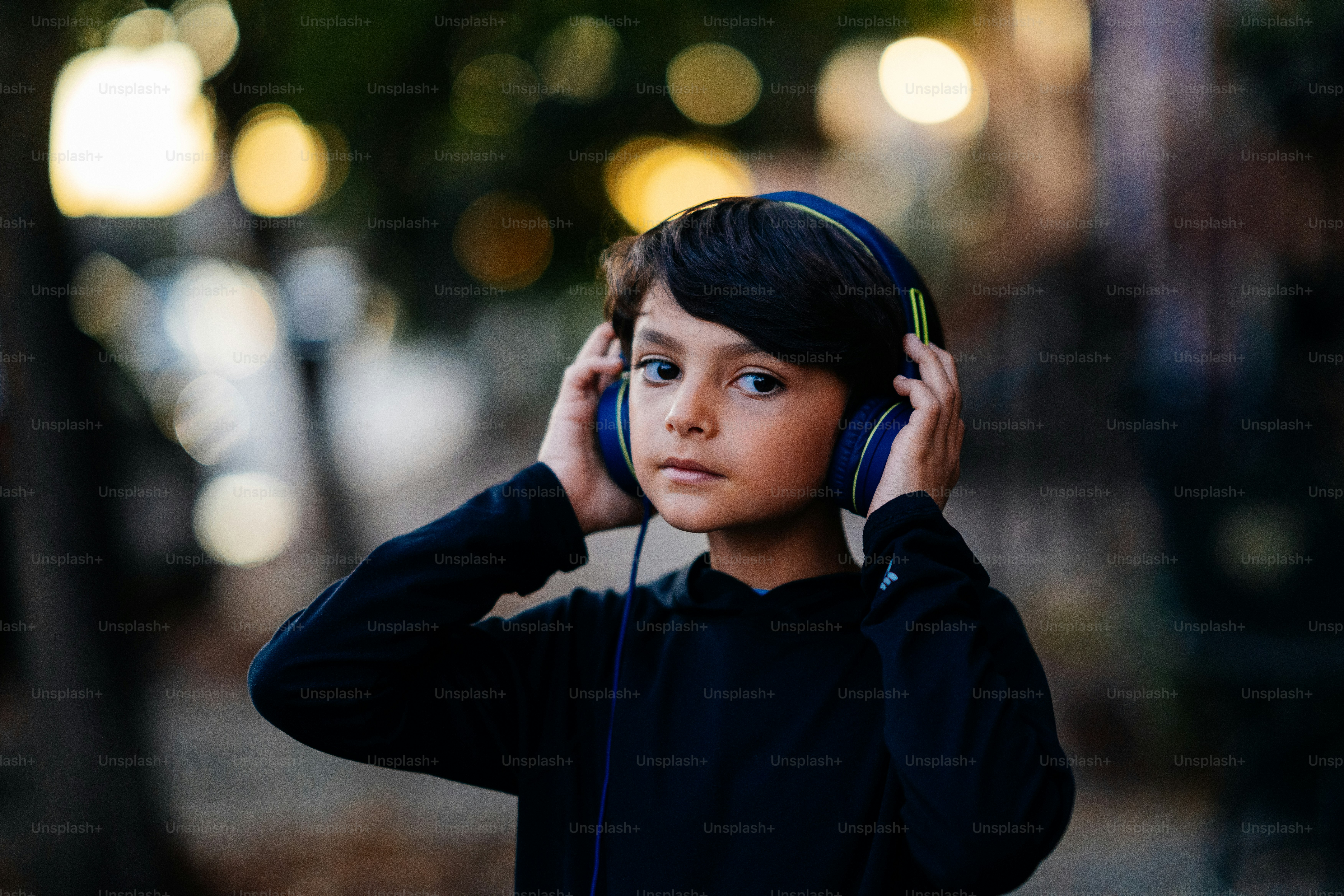 A young boy is listening to music with headphones photo – Music Image ...